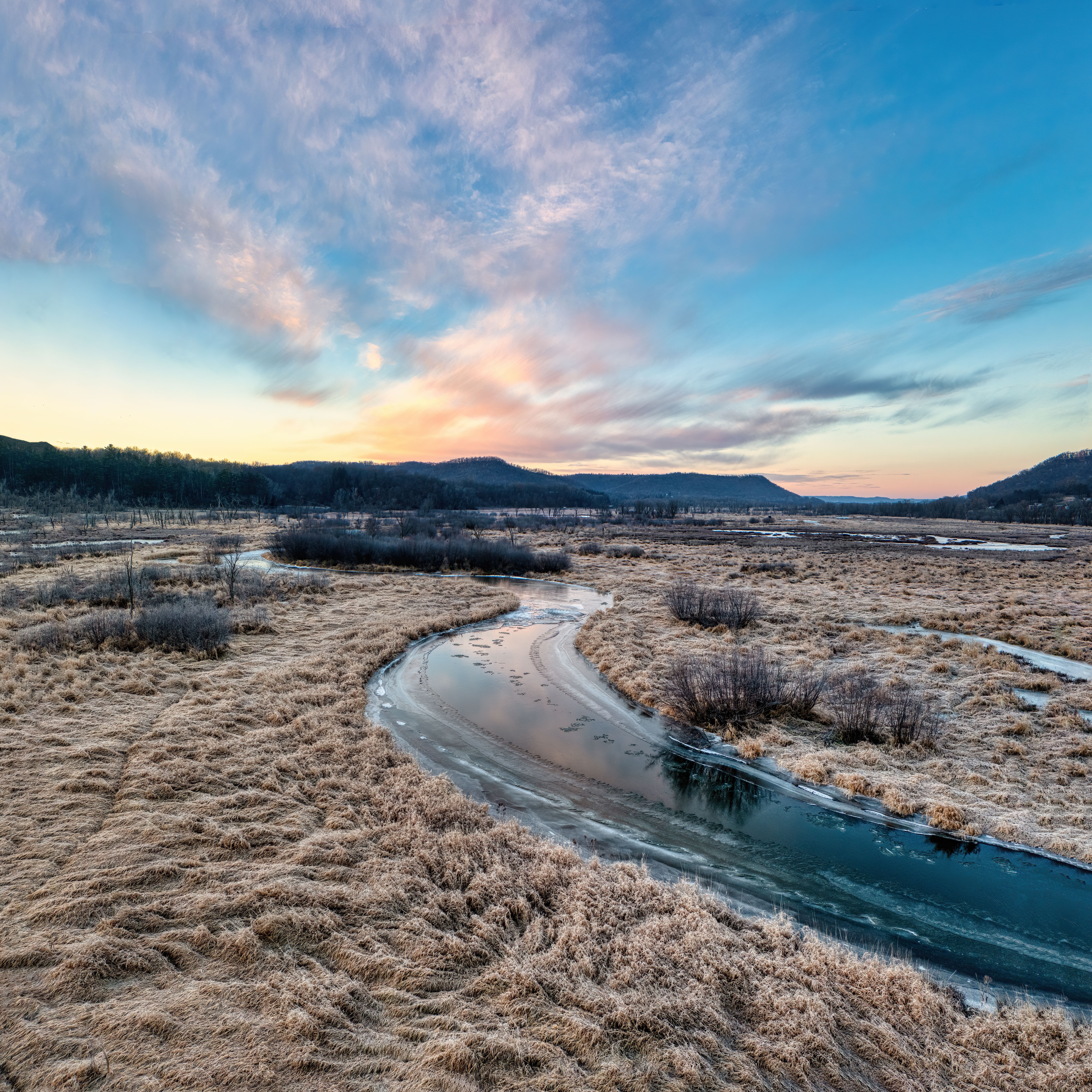 A river flows through a field at sunset · Free Stock Photo