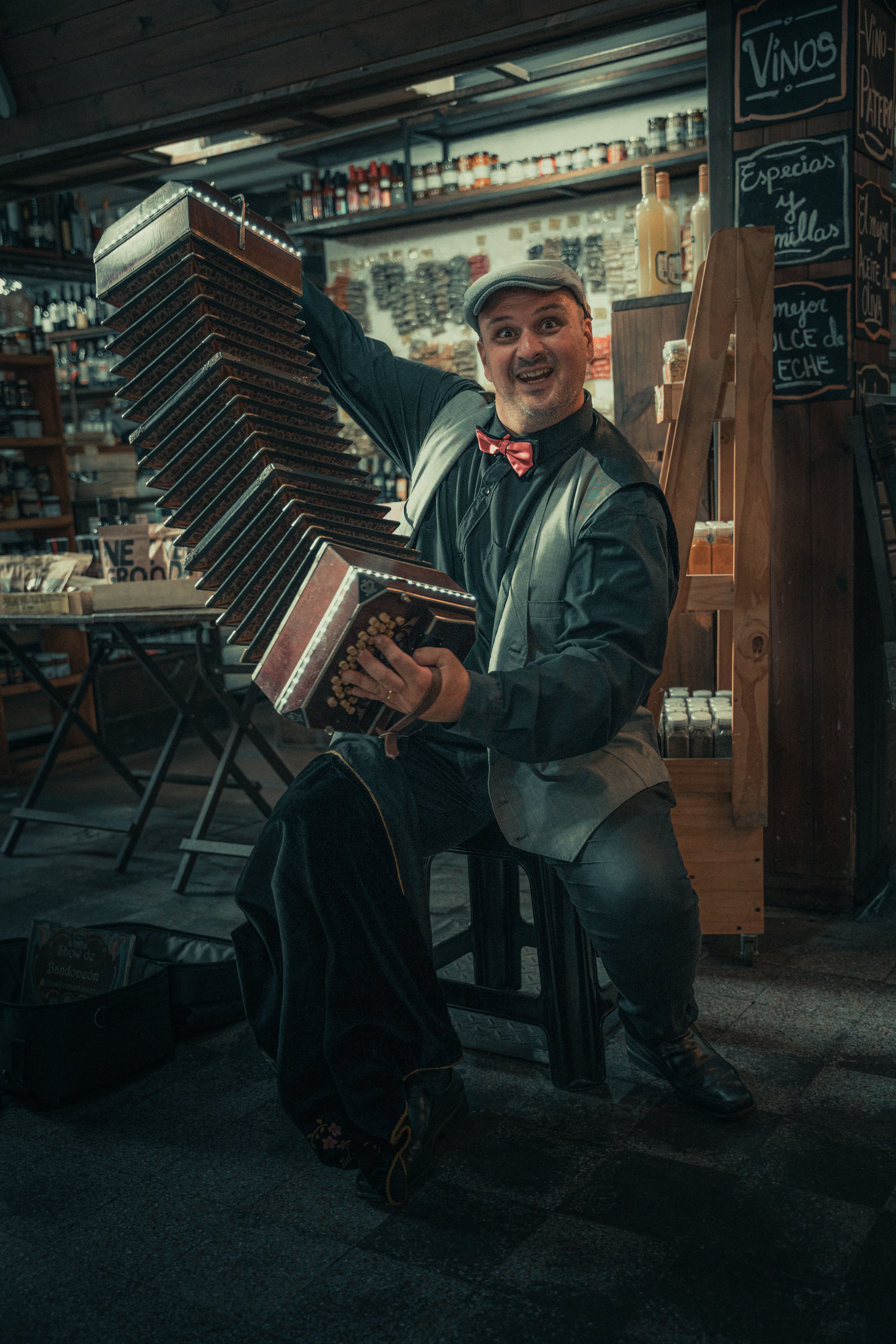 A Happy Man Holding a Bandoneon while Sitting near a Bar · Free Stock Photo