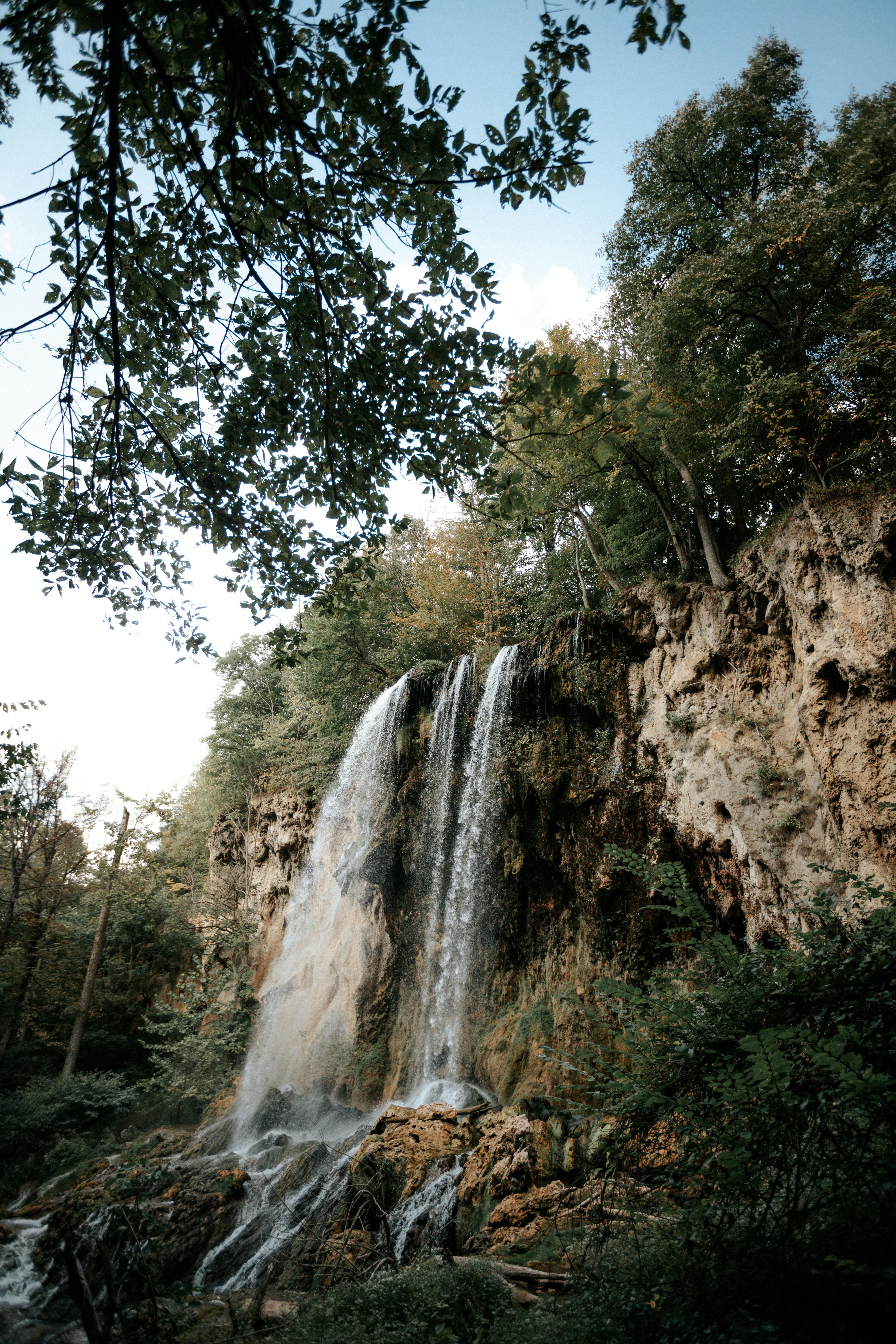 A waterfall is surrounded by trees and rocks · Free Stock Photo