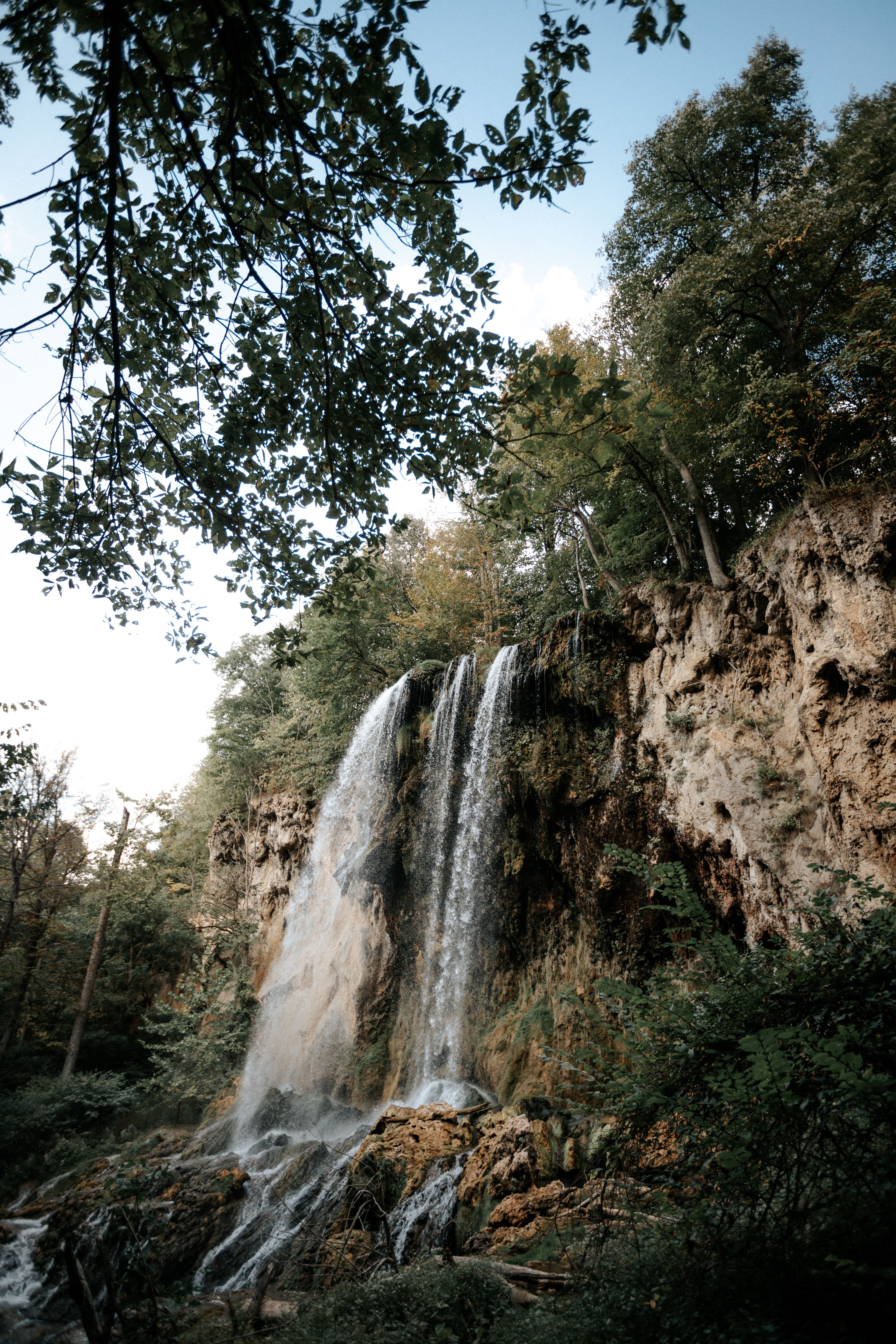 A waterfall is surrounded by trees and rocks · Free Stock Photo