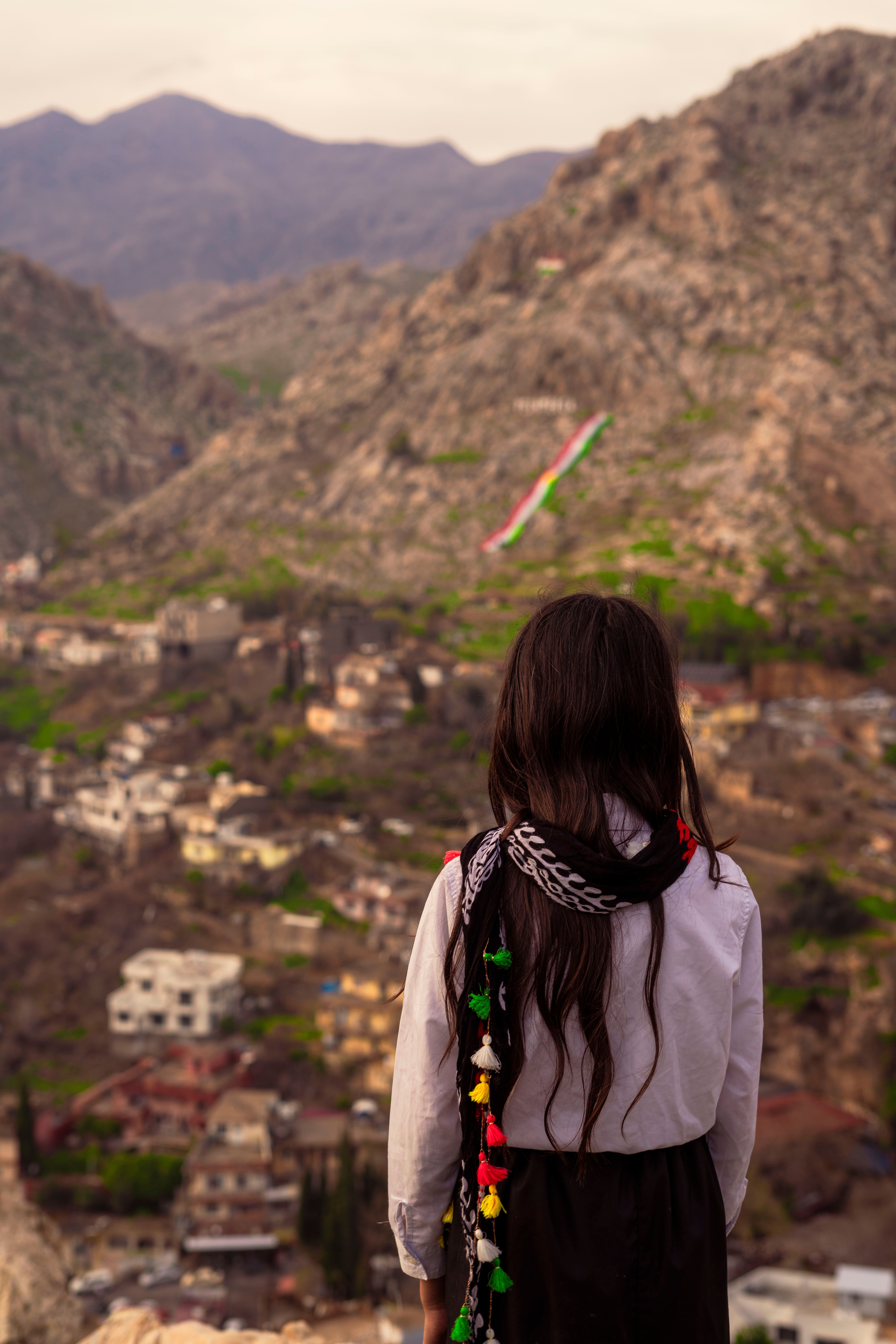 A woman looking out over a valley with mountains in the background ...