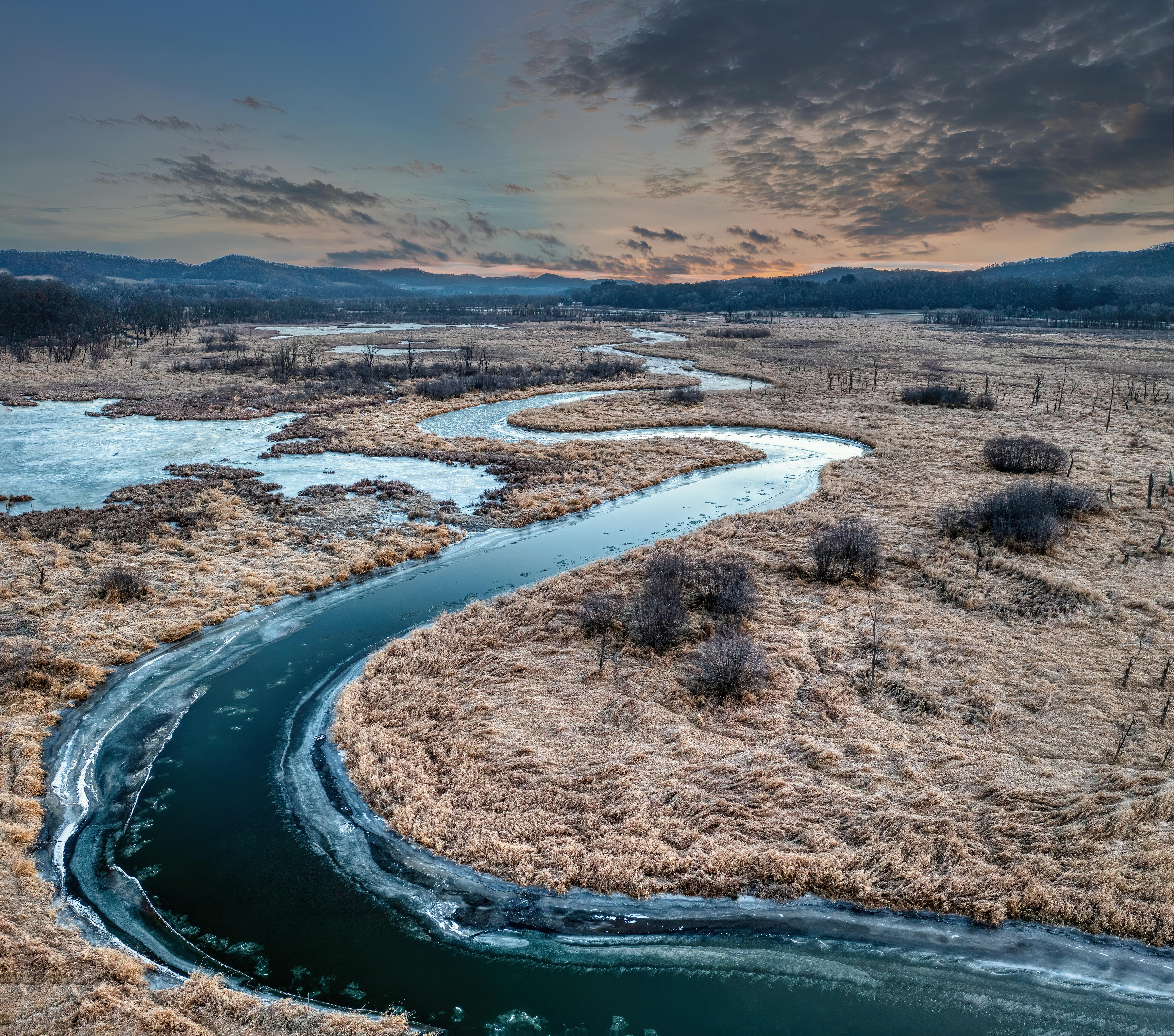 A river flows through a frozen landscape at sunset · Free Stock Photo
