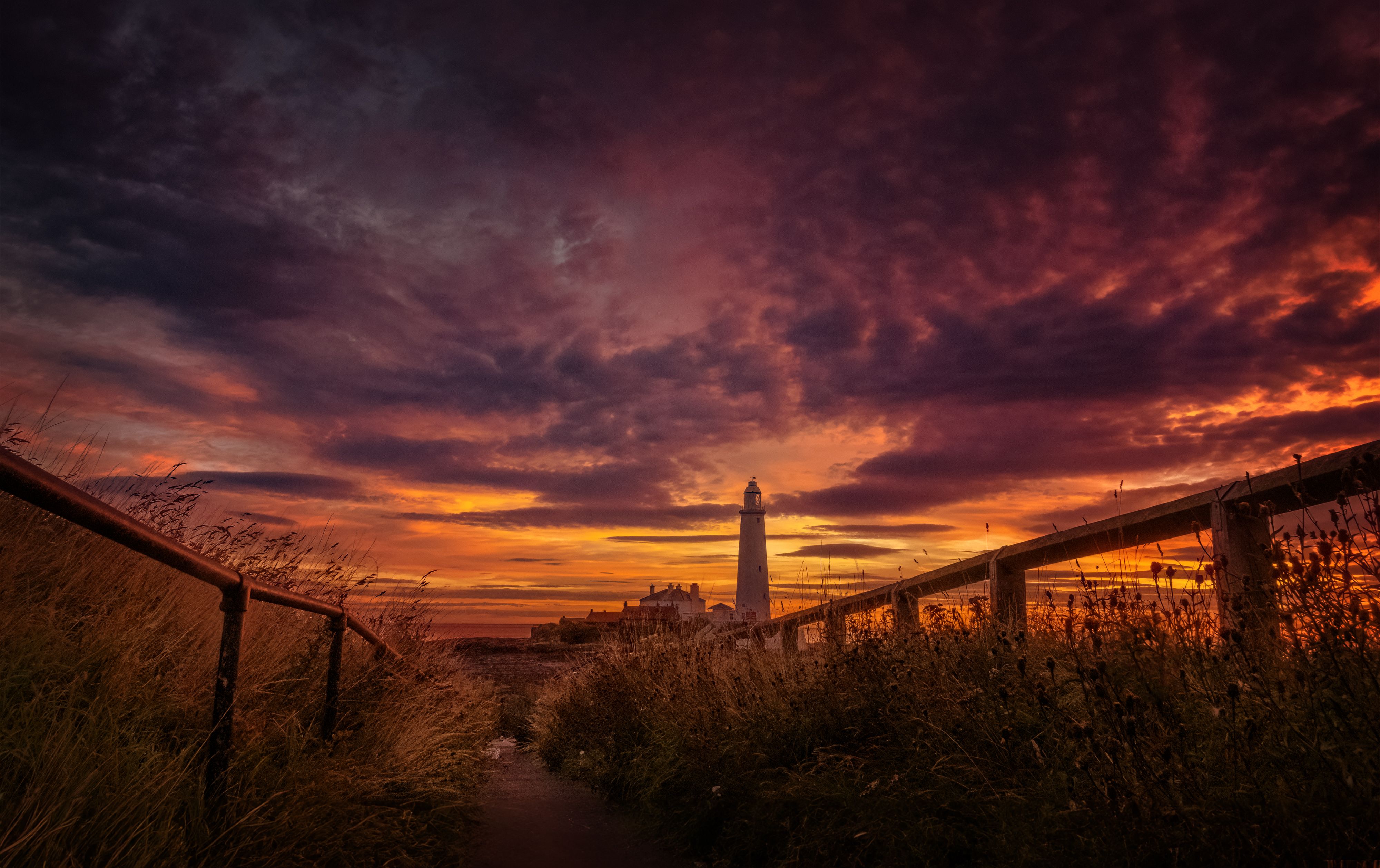 A sunset over a lighthouse and a path · Free Stock Photo