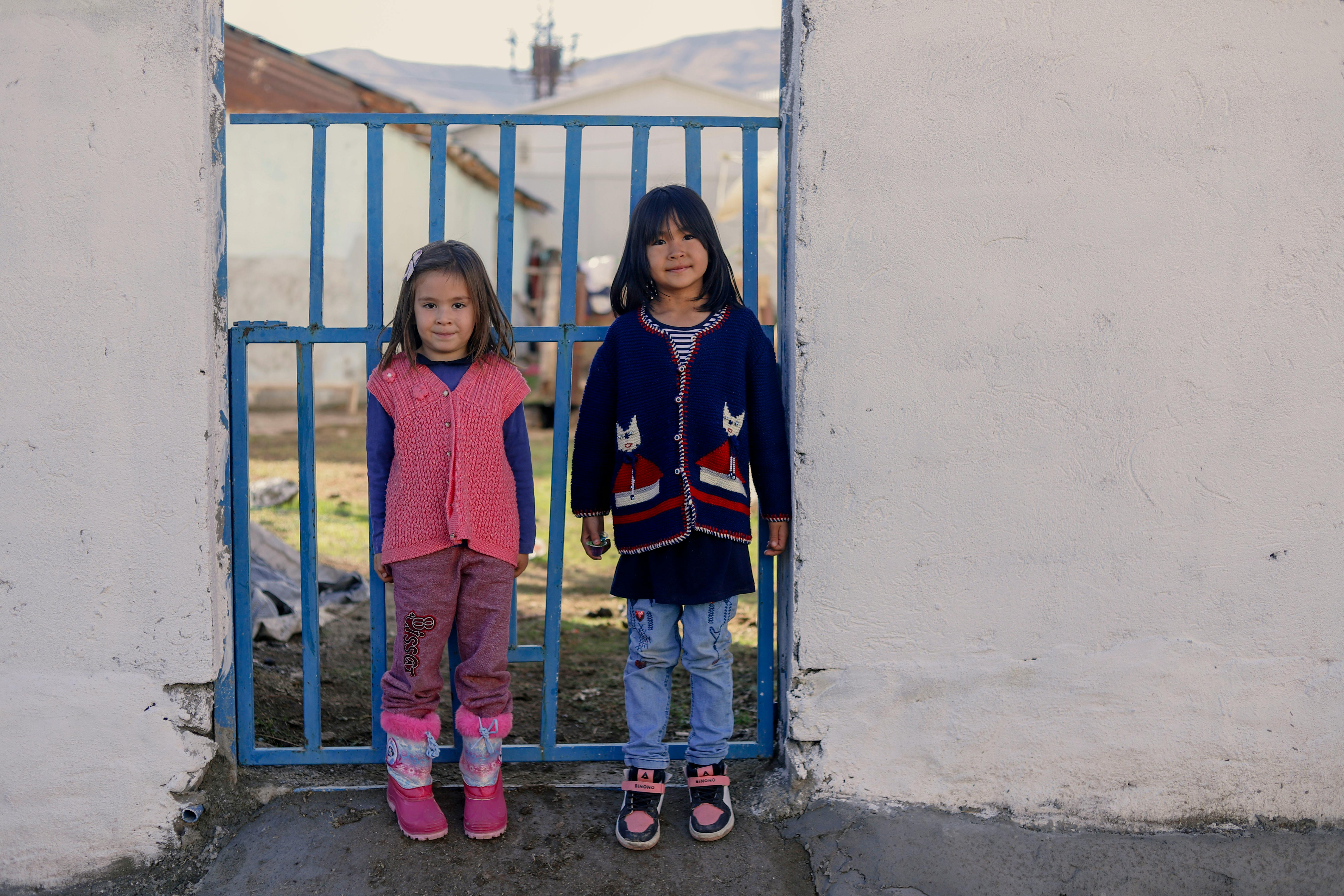 Two Little Girls Standing in Front of a Gate · Free Stock Photo