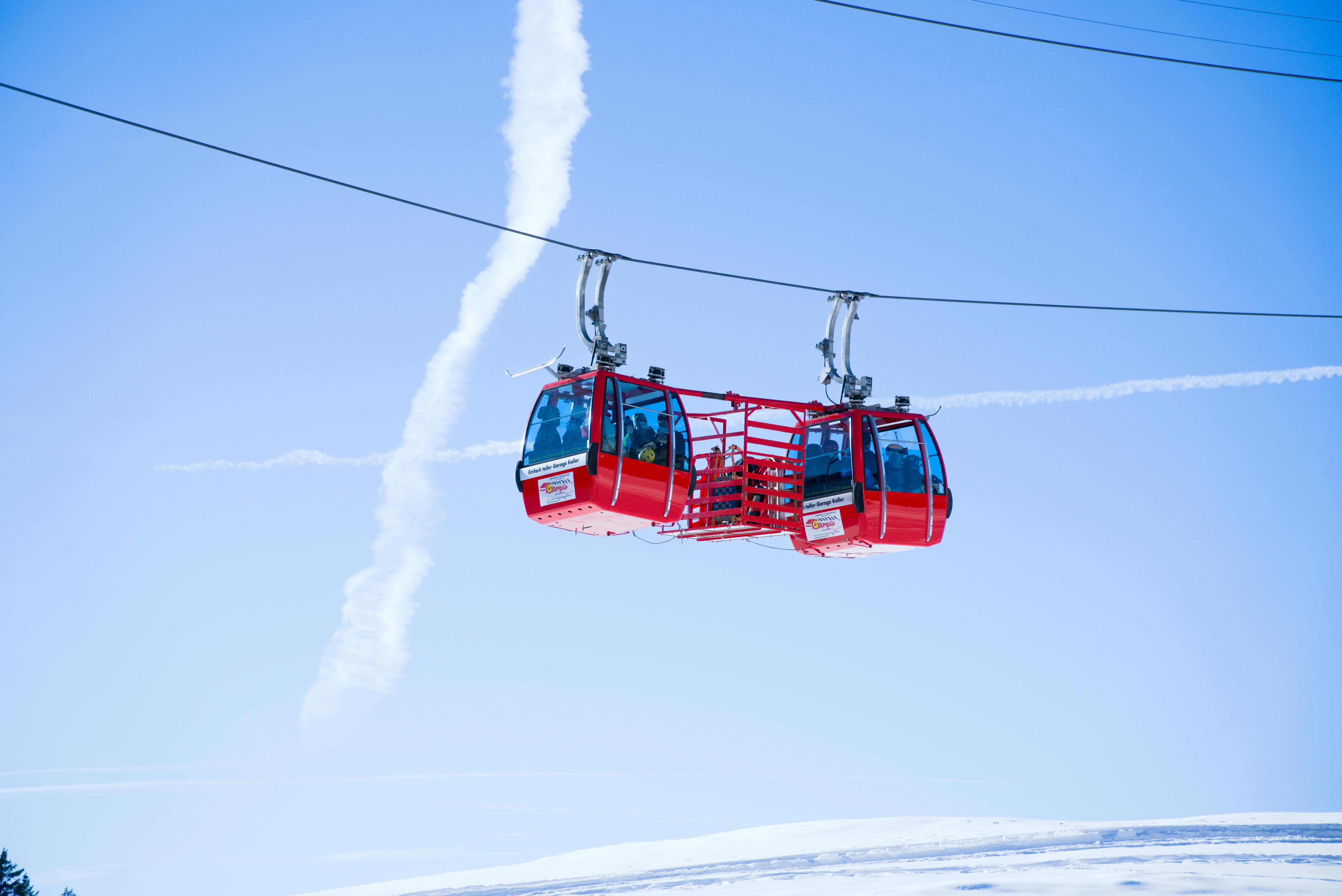 A red cable car with a white line going up · Free Stock Photo
