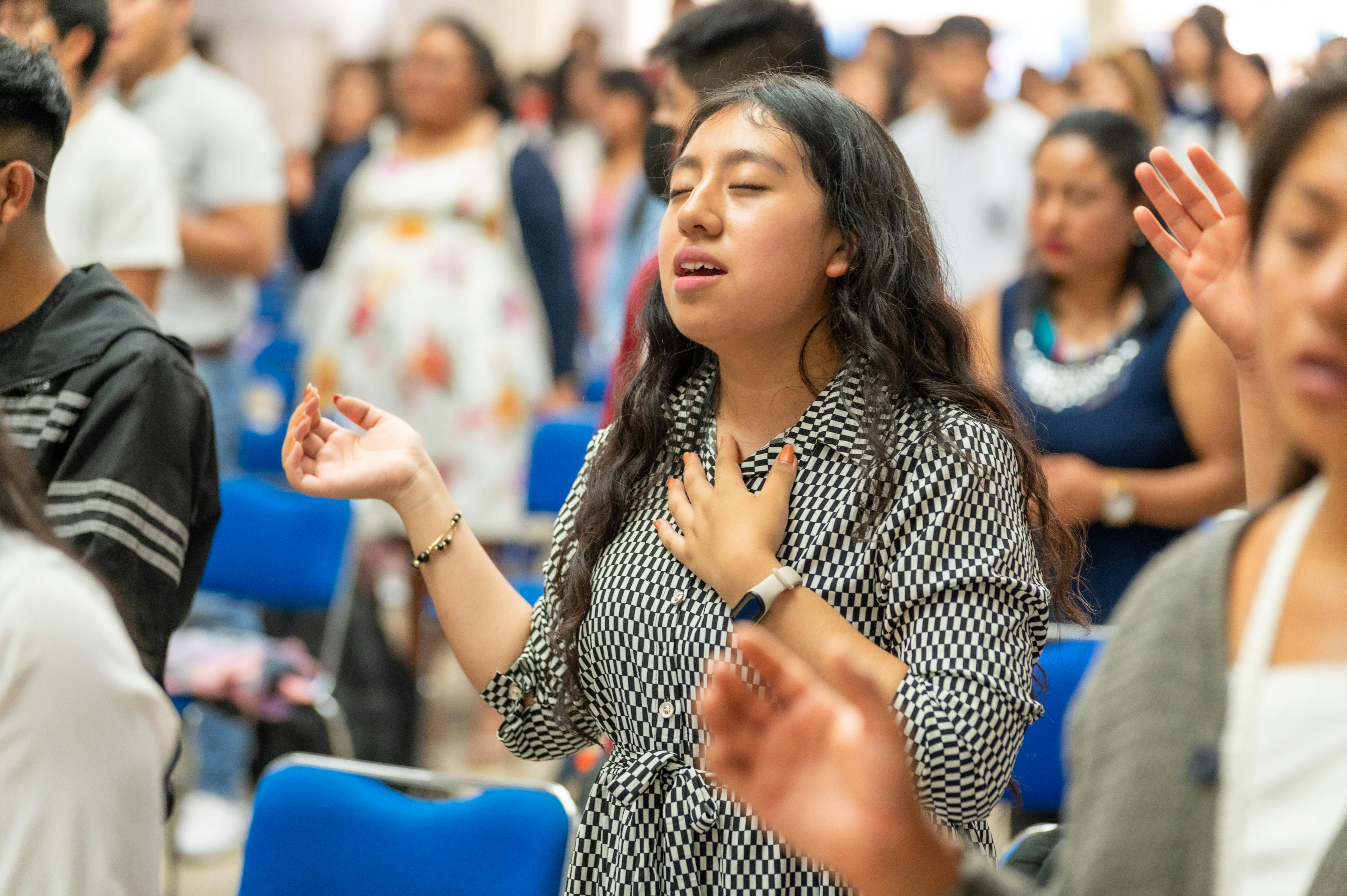 A woman is praying in a crowd of people · Free Stock Photo