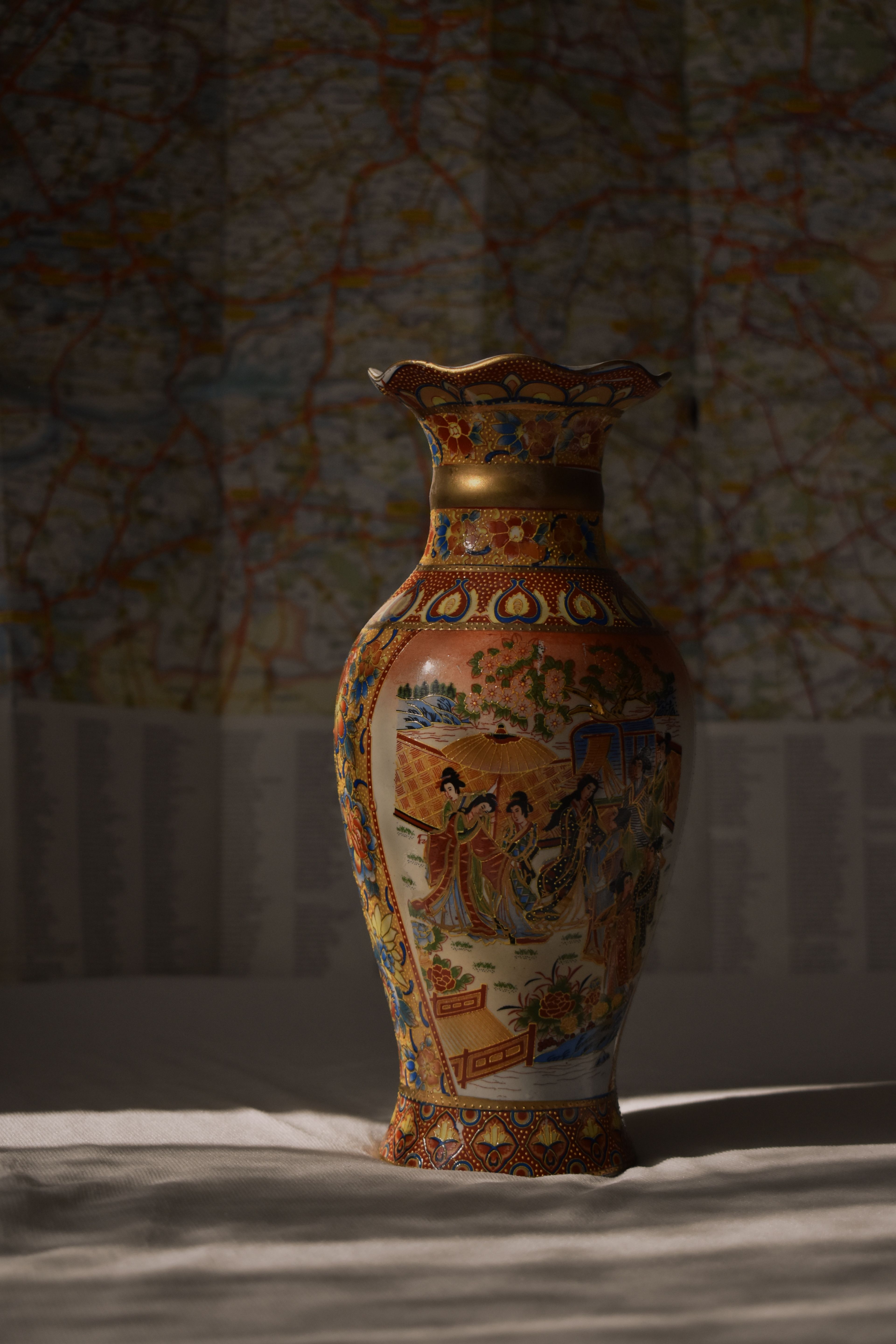 A vase on a table with a map behind it · Free Stock Photo