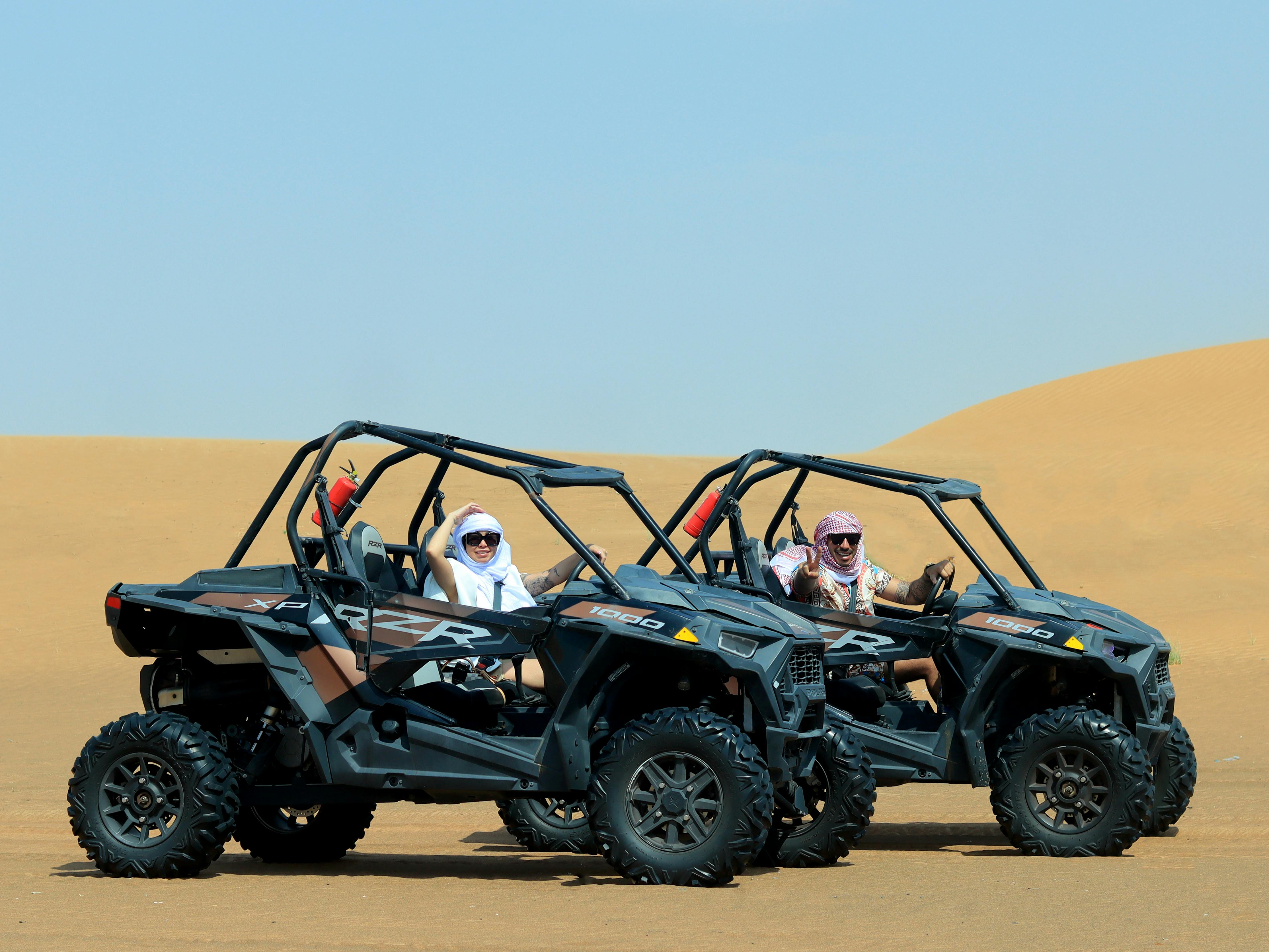 Man and Woman Riding Buggies on Desert · Free Stock Photo