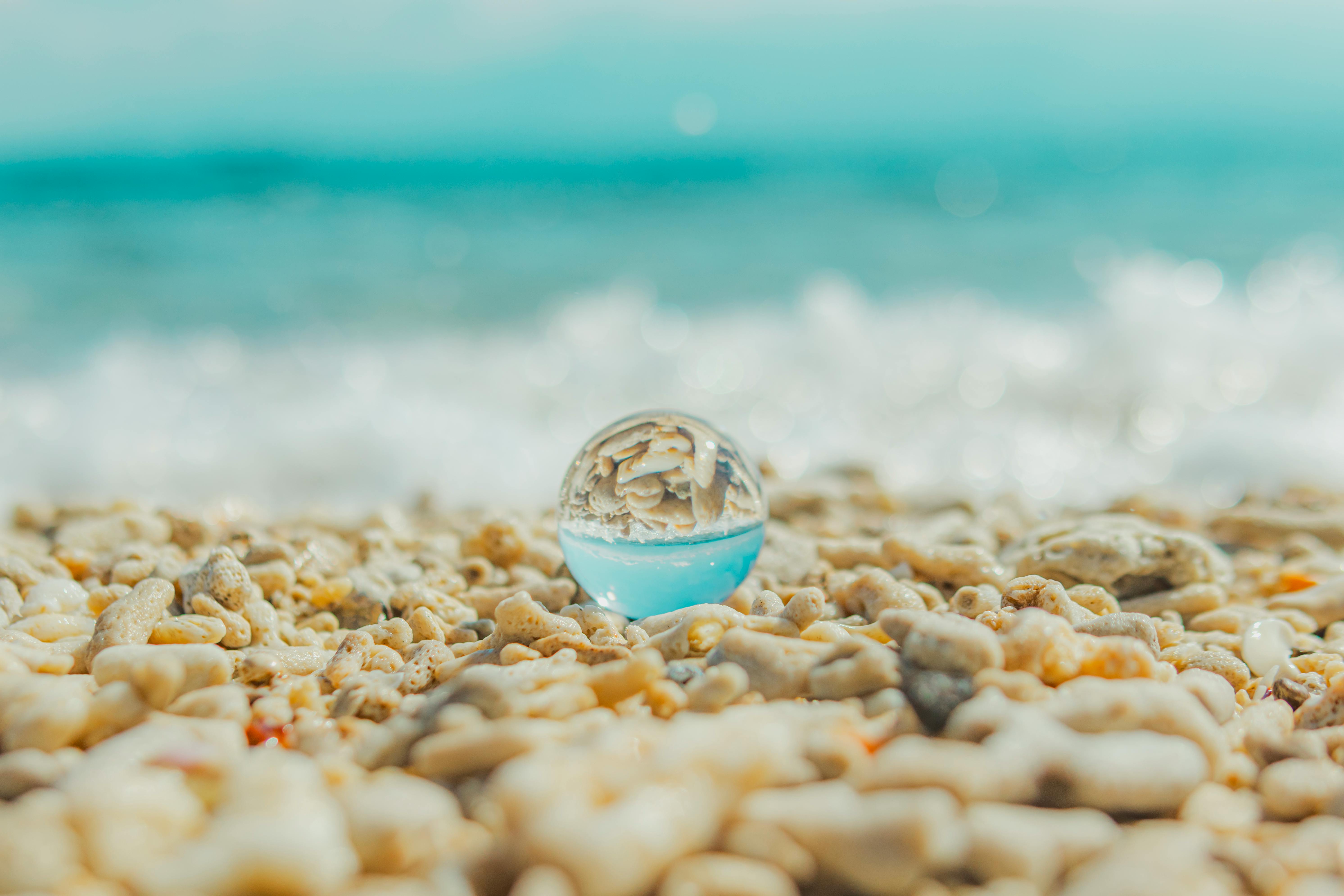 Reflection of Pebbles in Crystal Ball on Sea Shore · Free Stock Photo