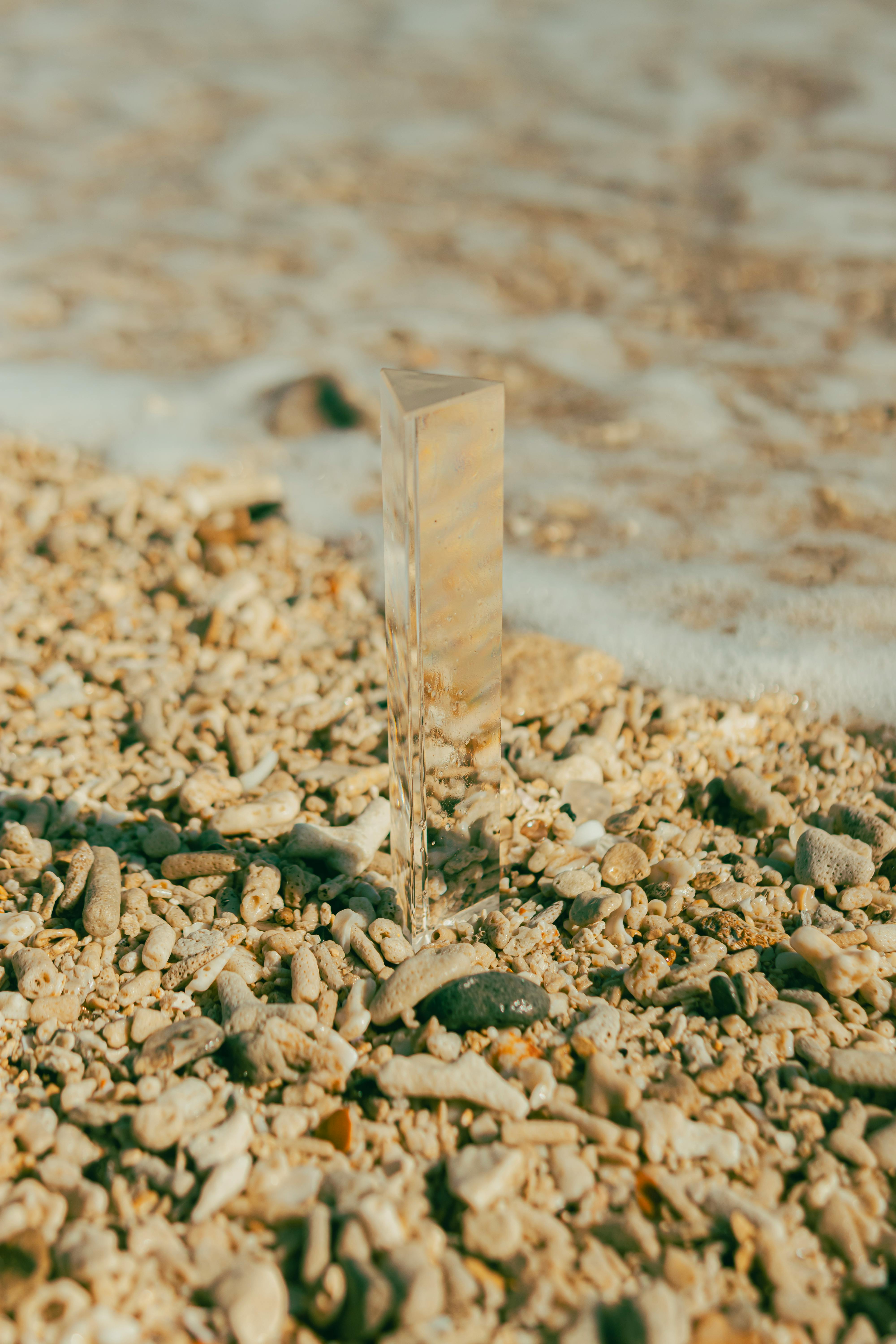 Close-up of a Clear Triangular Prism Standing on a Beach · Free Stock Photo