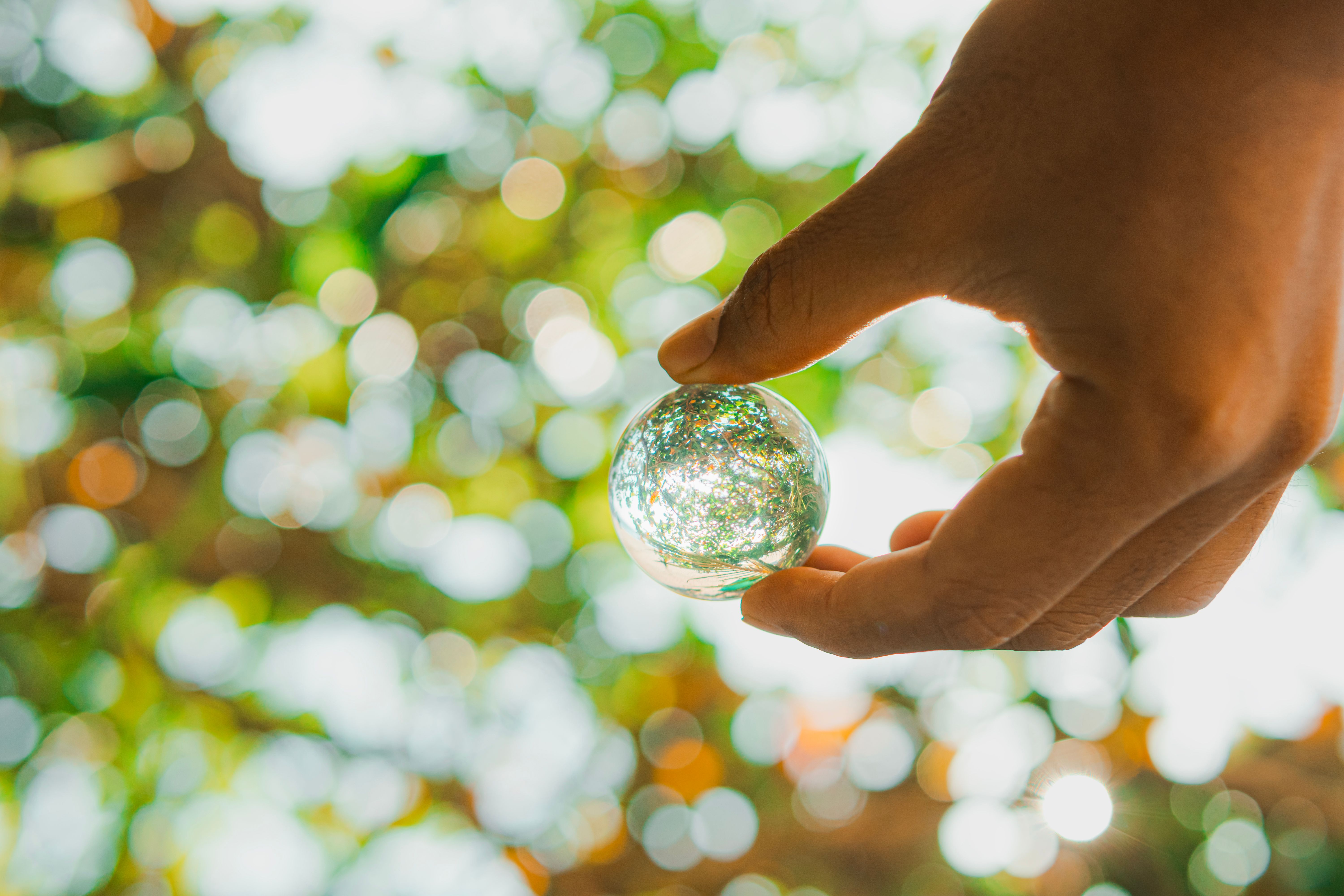 A person holding a glass sphere in their hand · Free Stock Photo