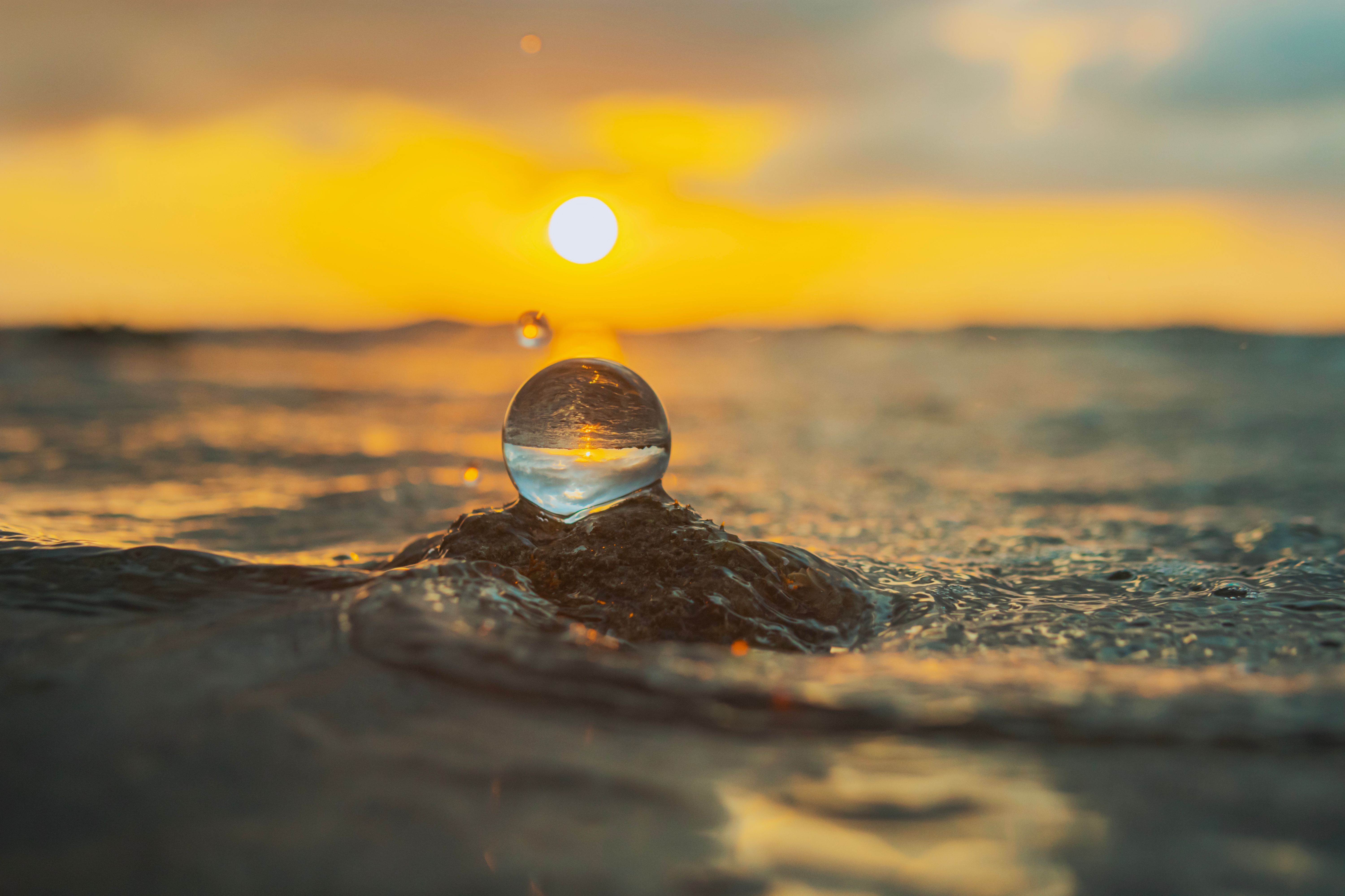 Close-up of a Clear Glass Ball Lying on a Beach at Sunset · Free Stock ...