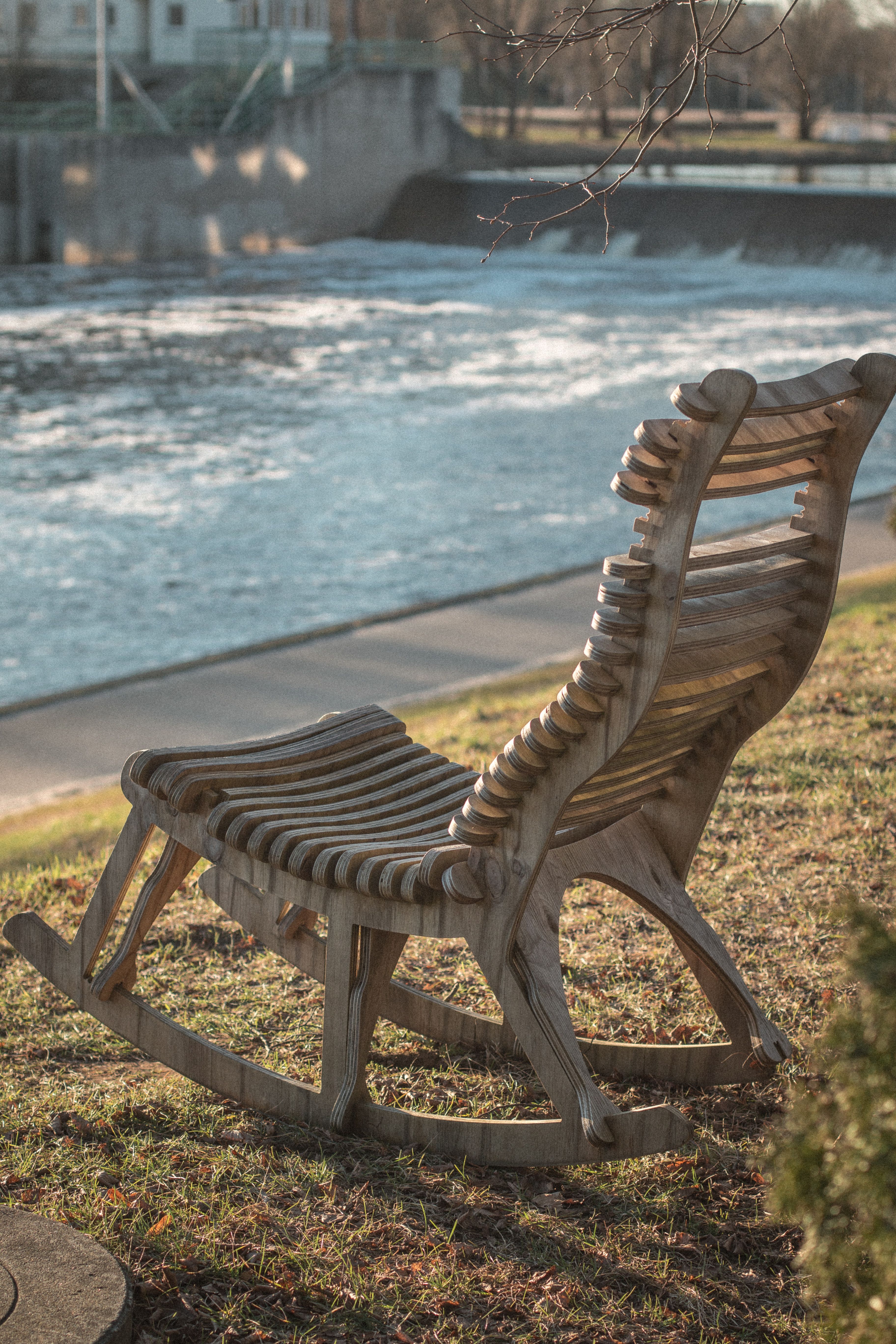 A rocking chair sitting on the grass near a river · Free Stock Photo