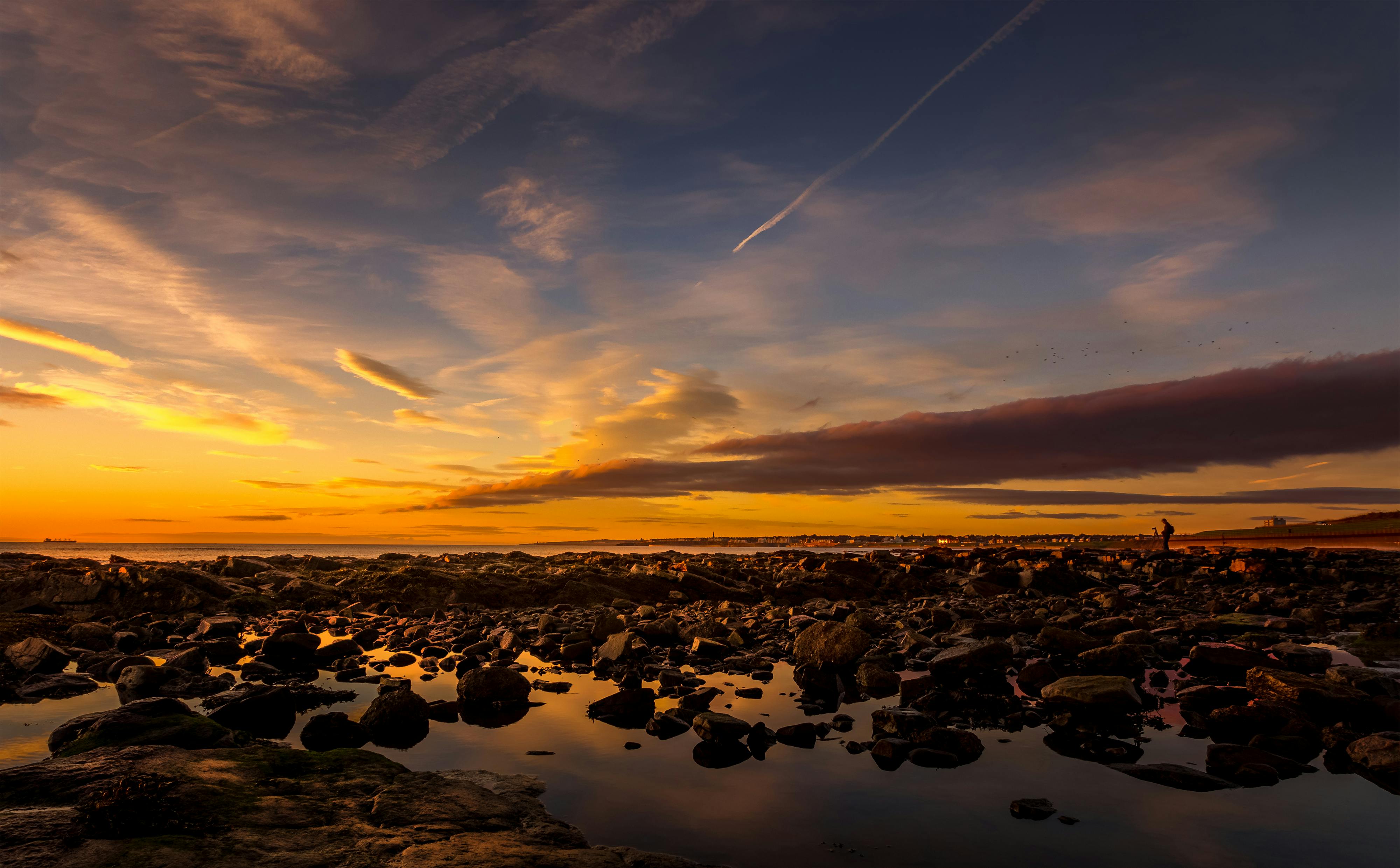 Dramatic Sunset over Rocks Lying on Sea Shore · Free Stock Photo