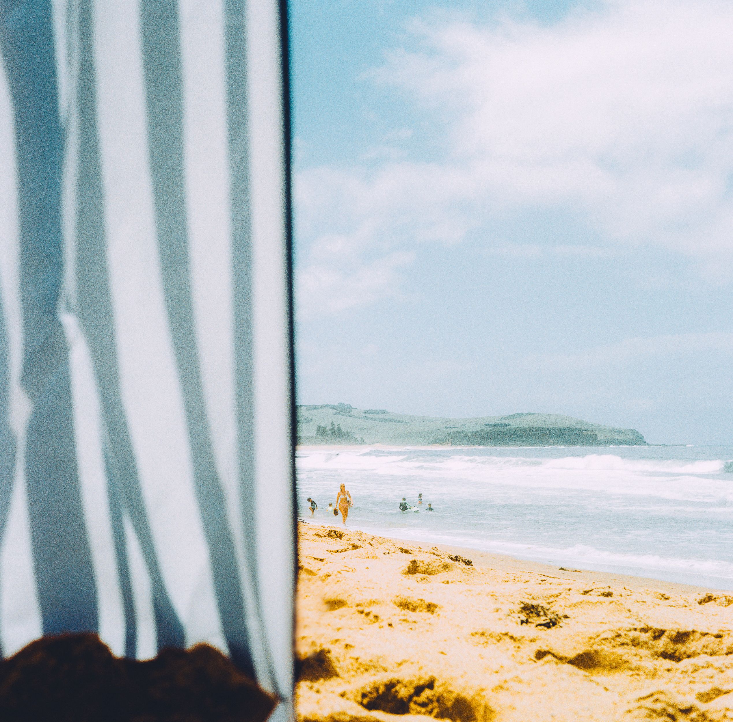 People Swimming in Sea seen from behind Beach Tent · Free Stock Photo