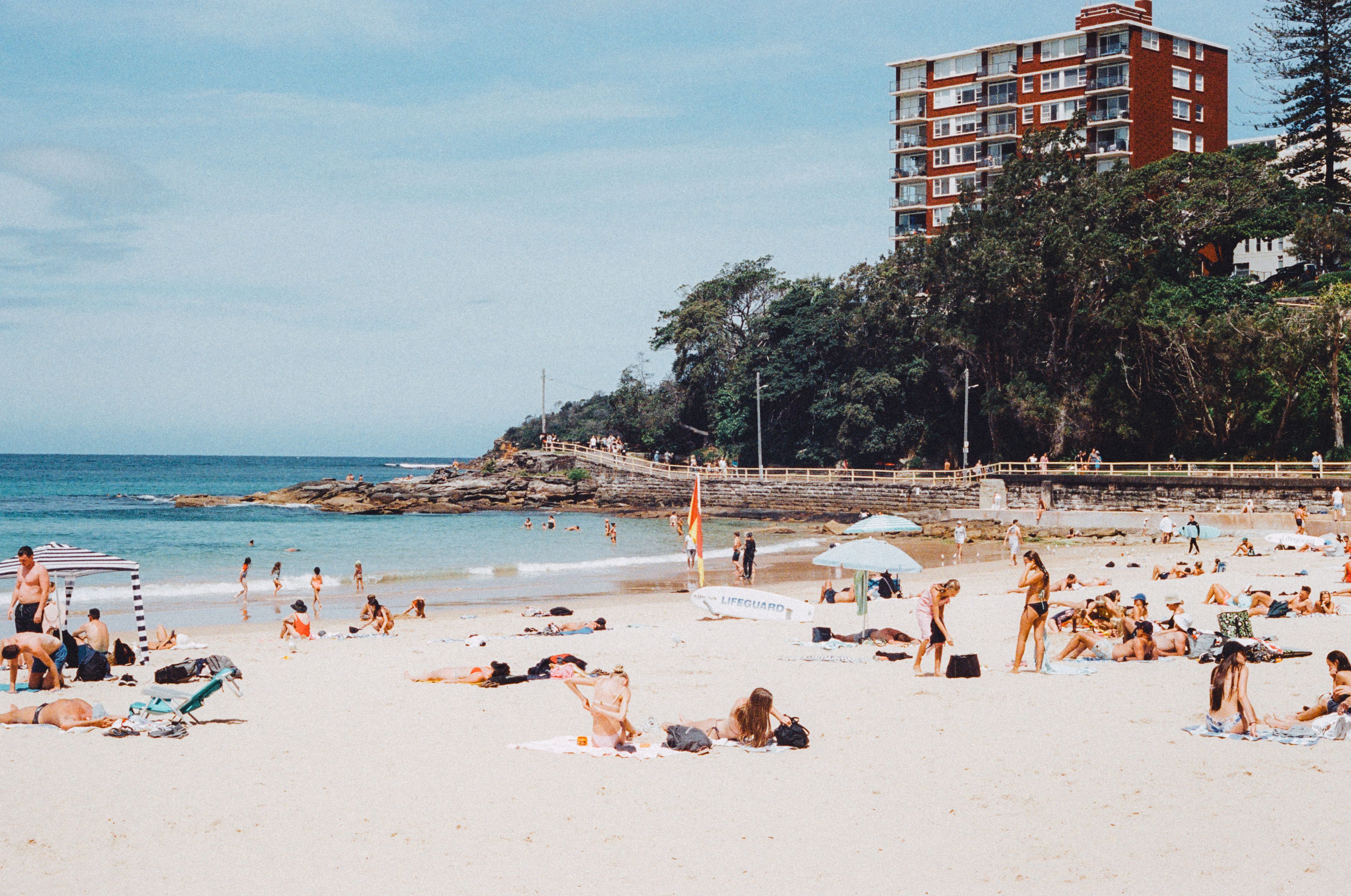 People at Beach by Sea in front of High Rise Buil · Free Stock Photo