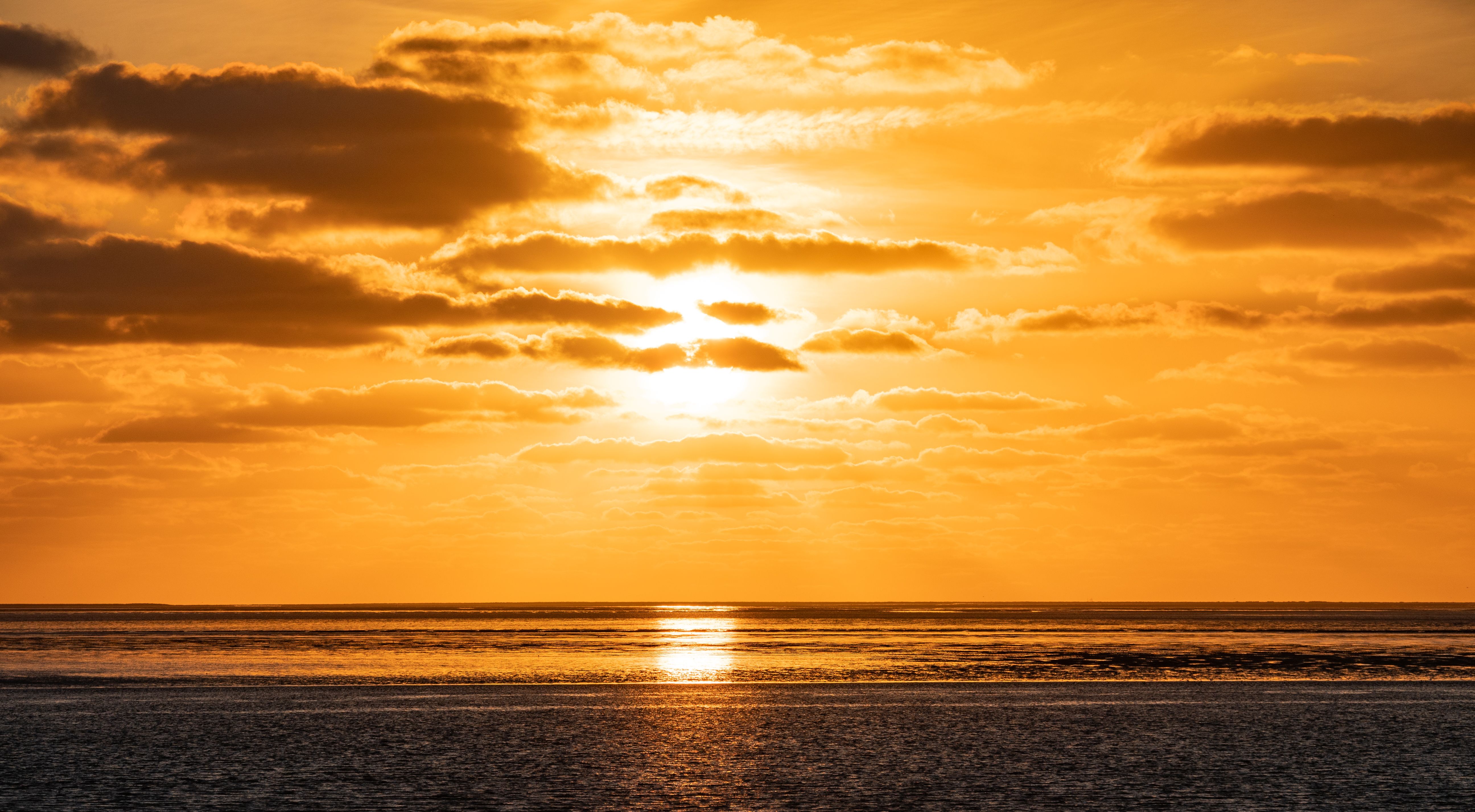 A sunset over the ocean with clouds and water · Free Stock Photo