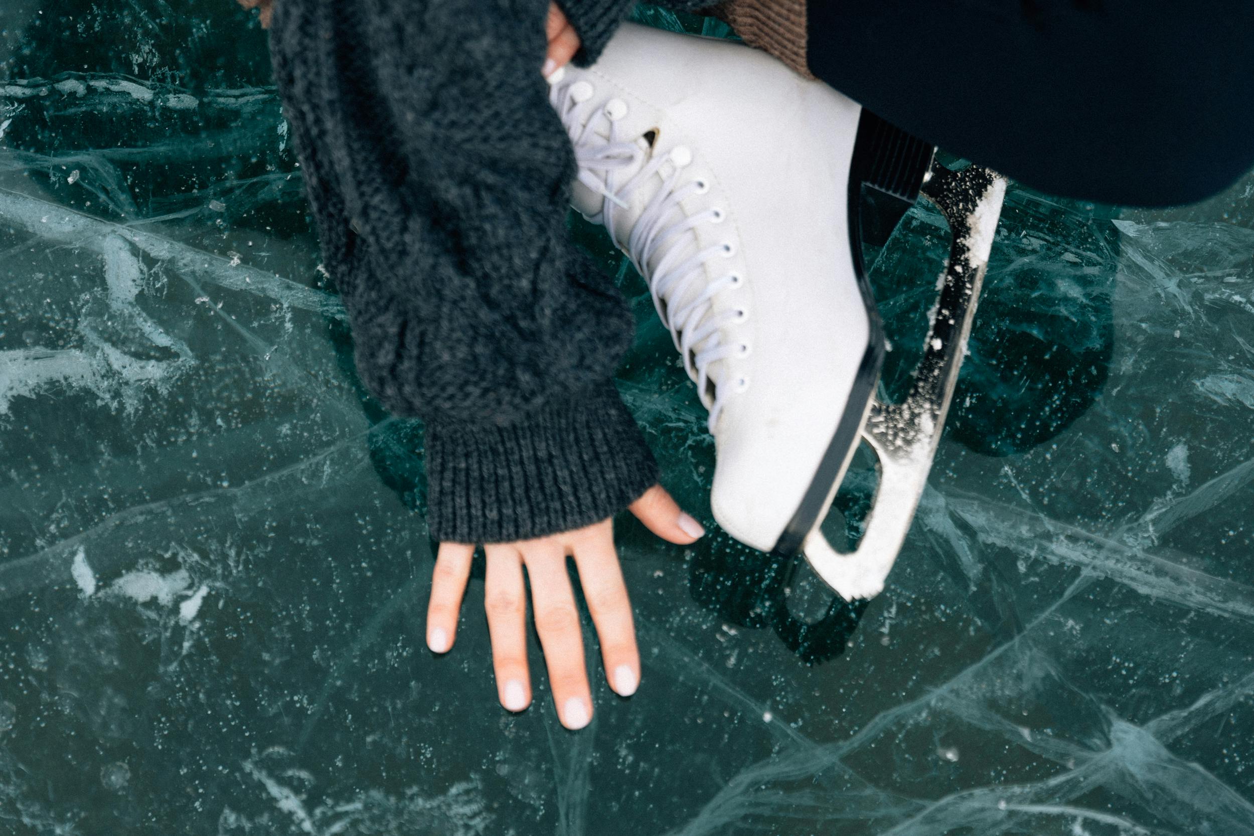 Hand of a Woman Wearing Ice Skates Touching the Surface of a Frozen ...