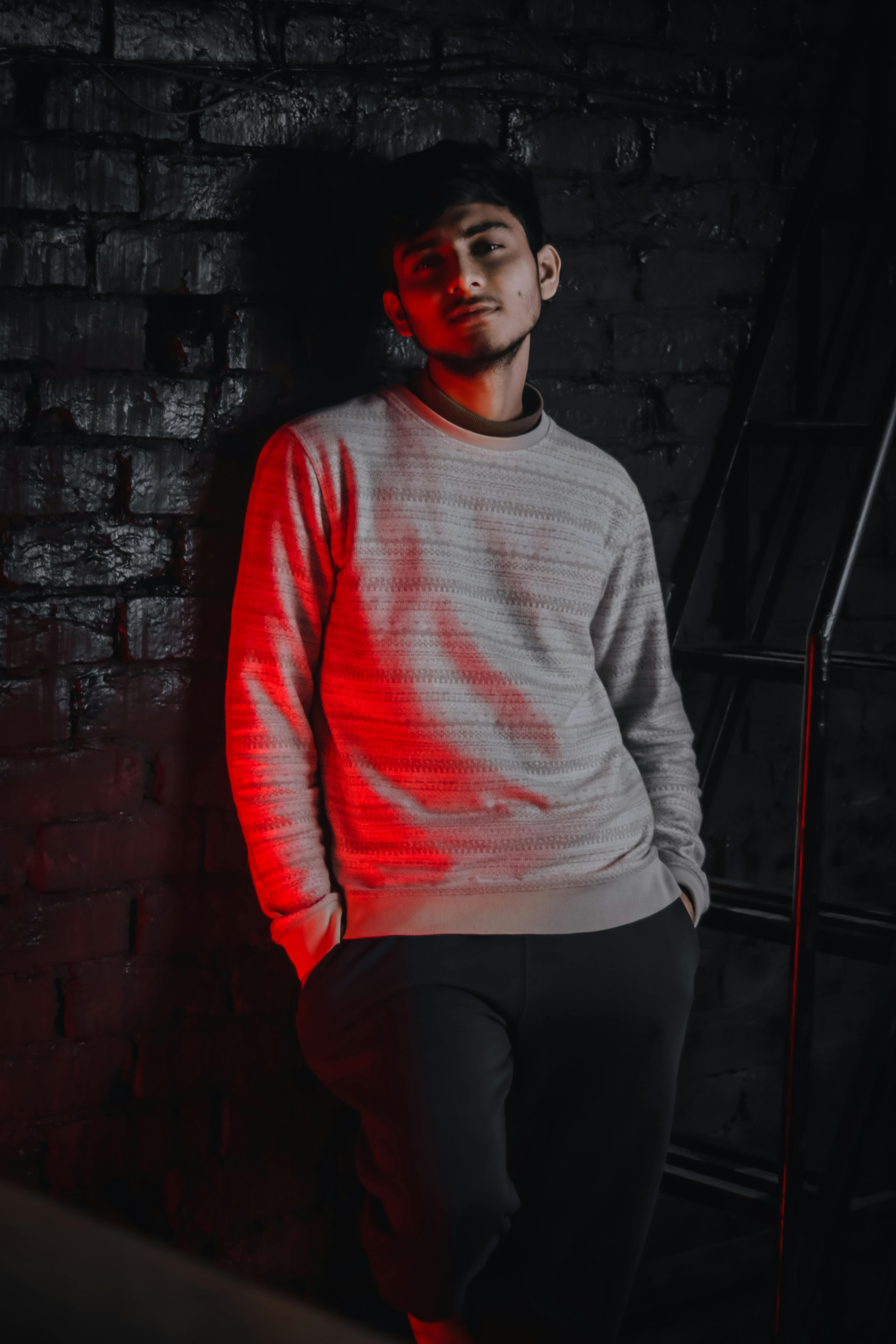 Young Man Posing in a Red Light Reflection against a Black Brick Wall ...
