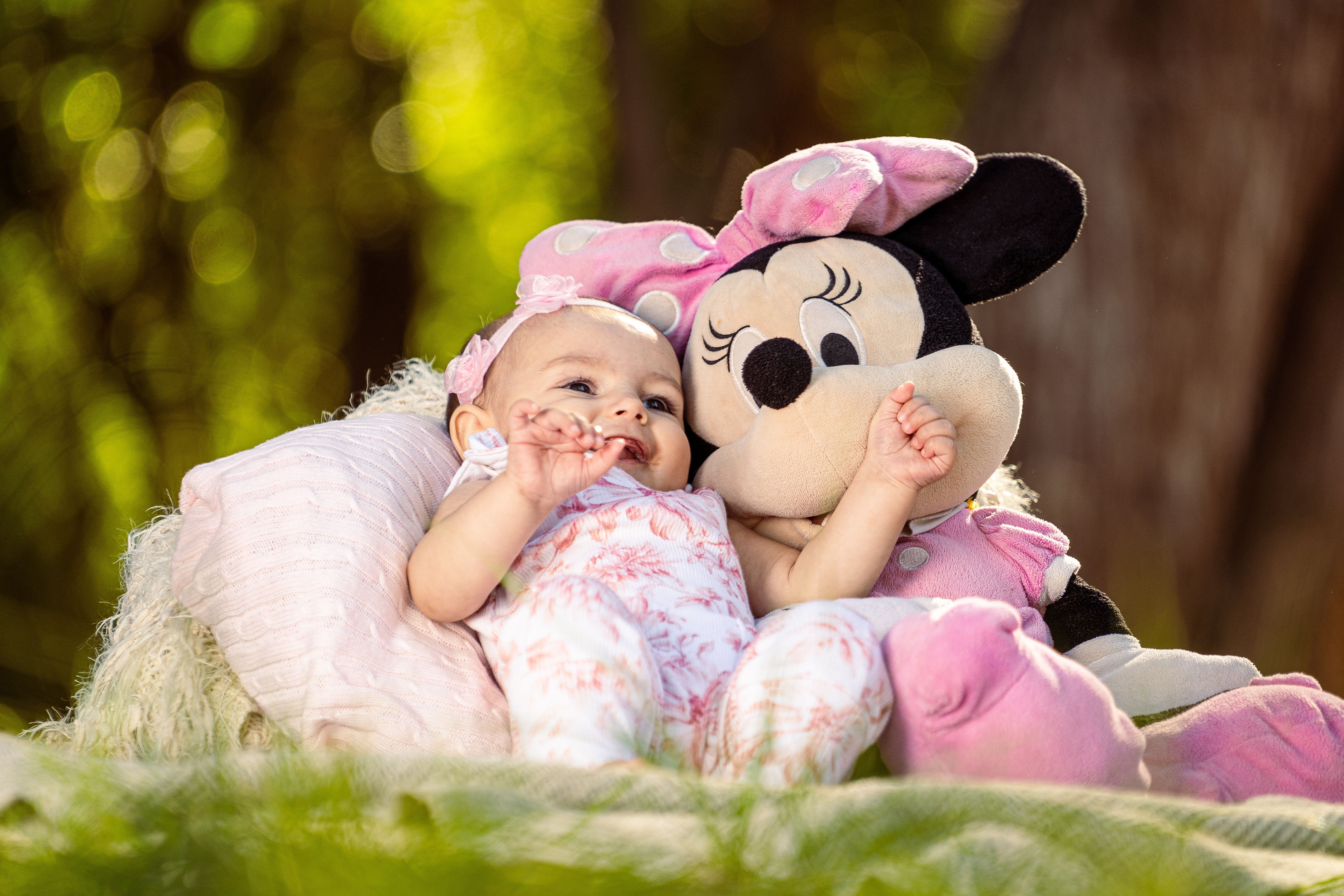 A baby girl and minnie mouse are laying on the grass · Free Stock Photo