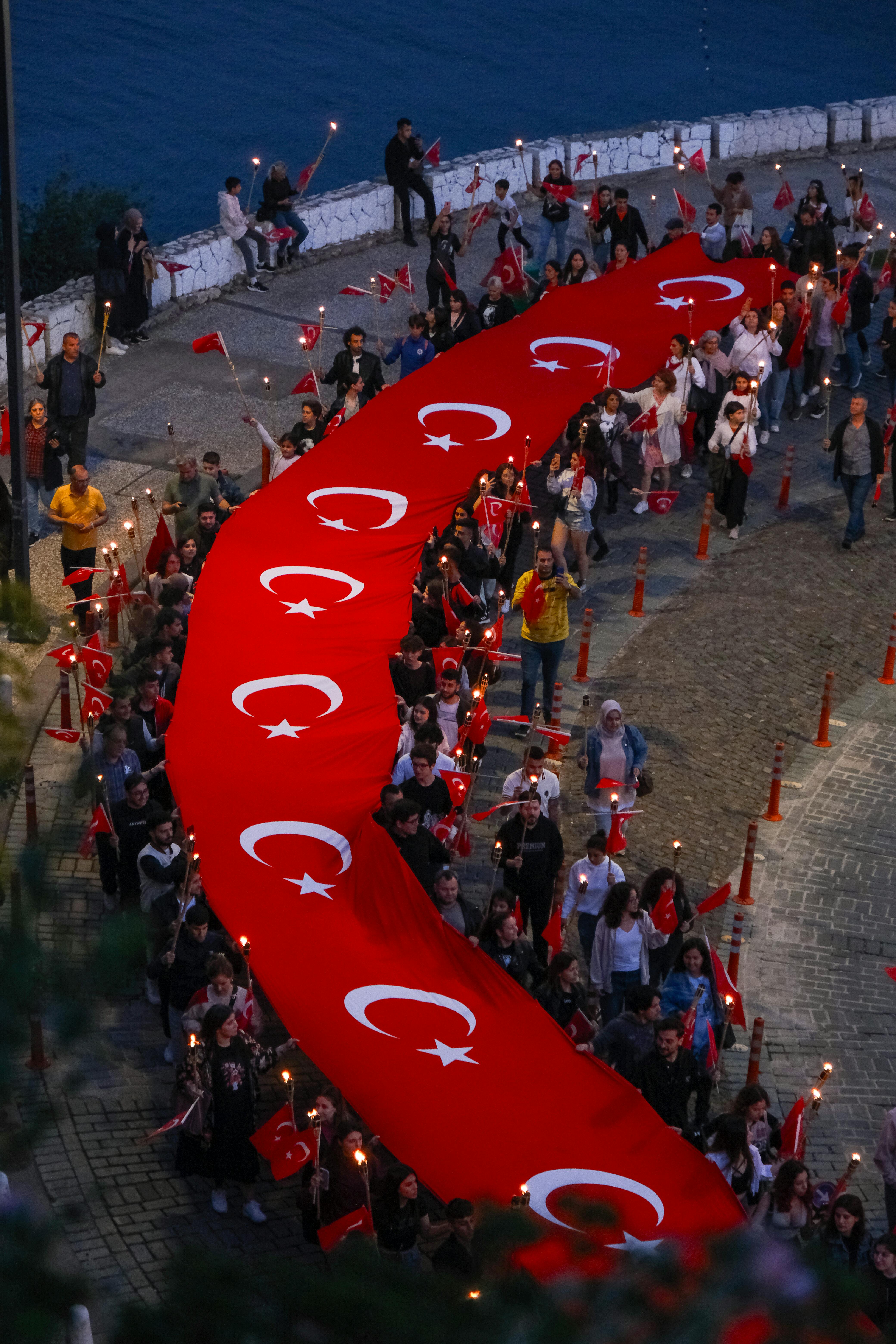Twilight march along a coastal path with a large Turkish flag and ...