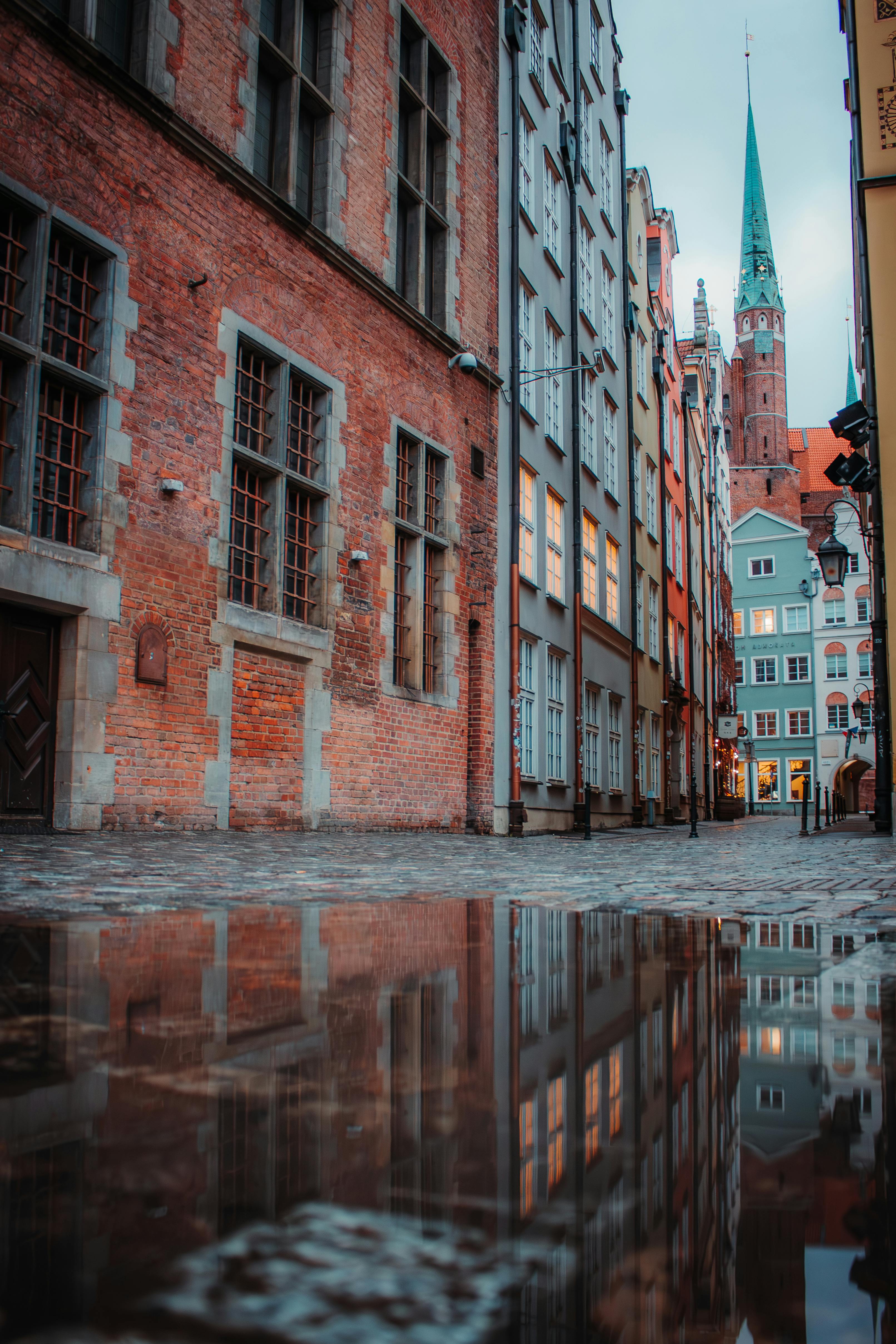 Tower and Buildings in Gdansk Old Town Reflection in Puddle on Street · Free Stock Photo