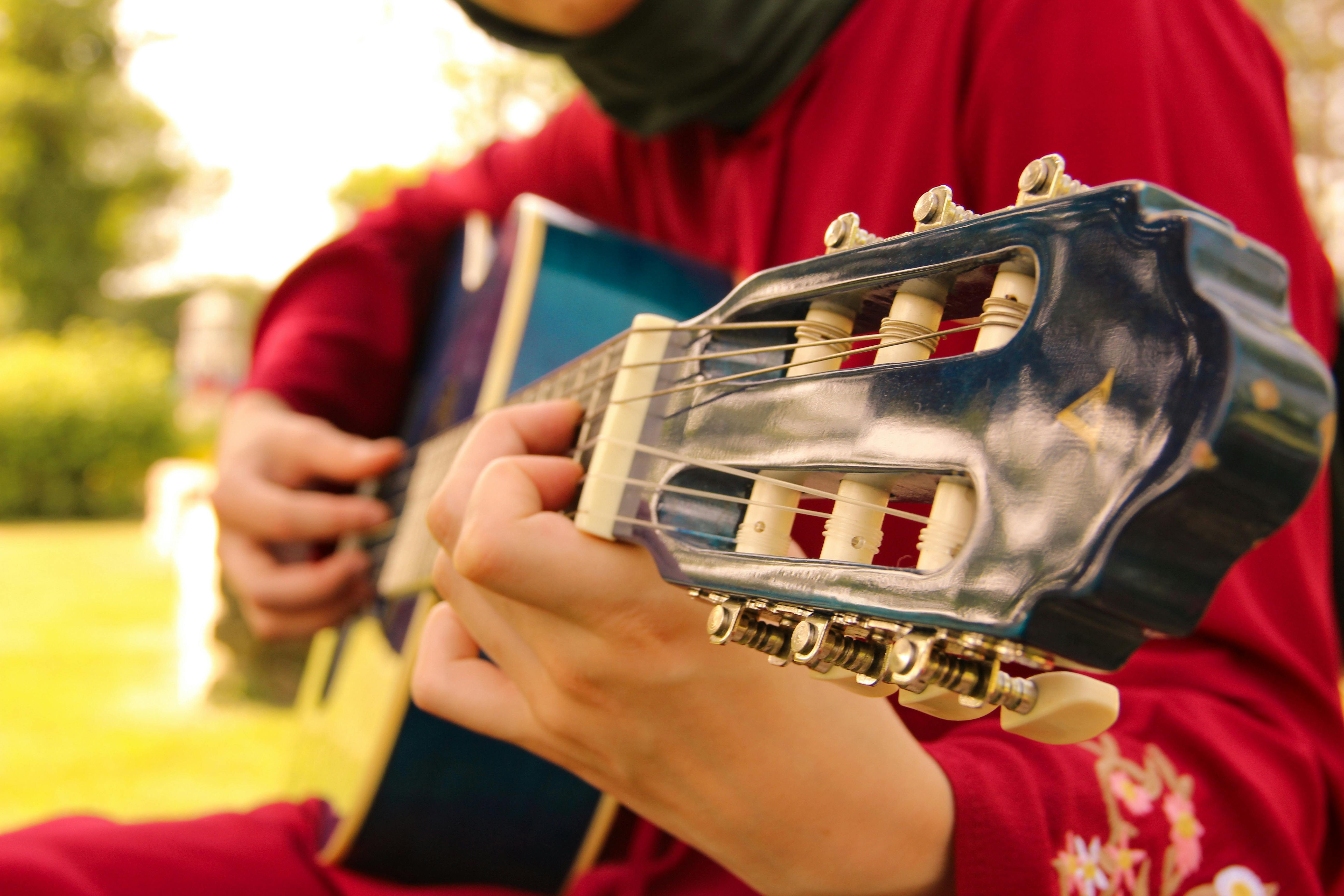 Muslim woman playing guitar in the park · Free Stock Photo