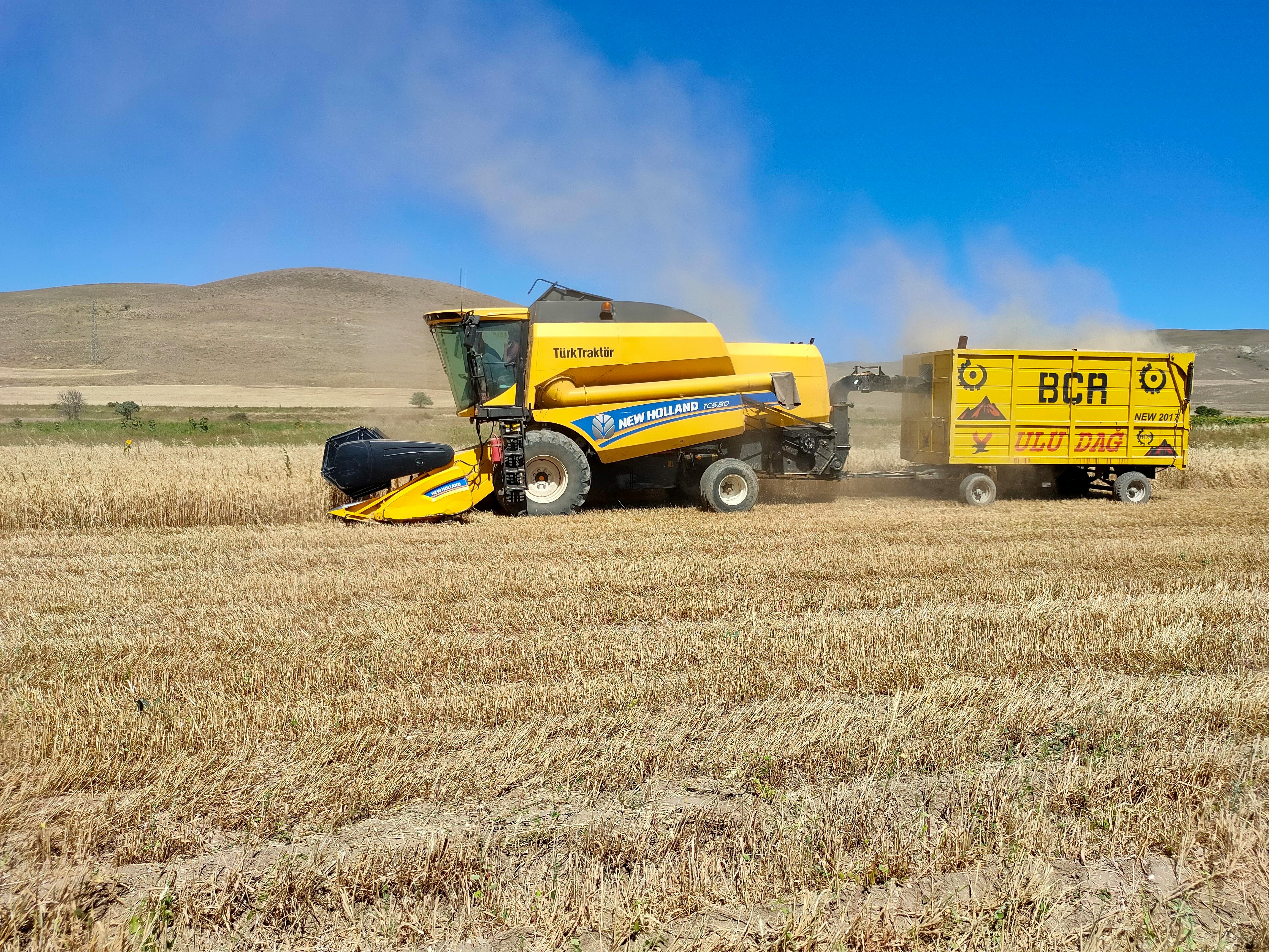 A yellow and blue combine harvester in a field · Free Stock Photo