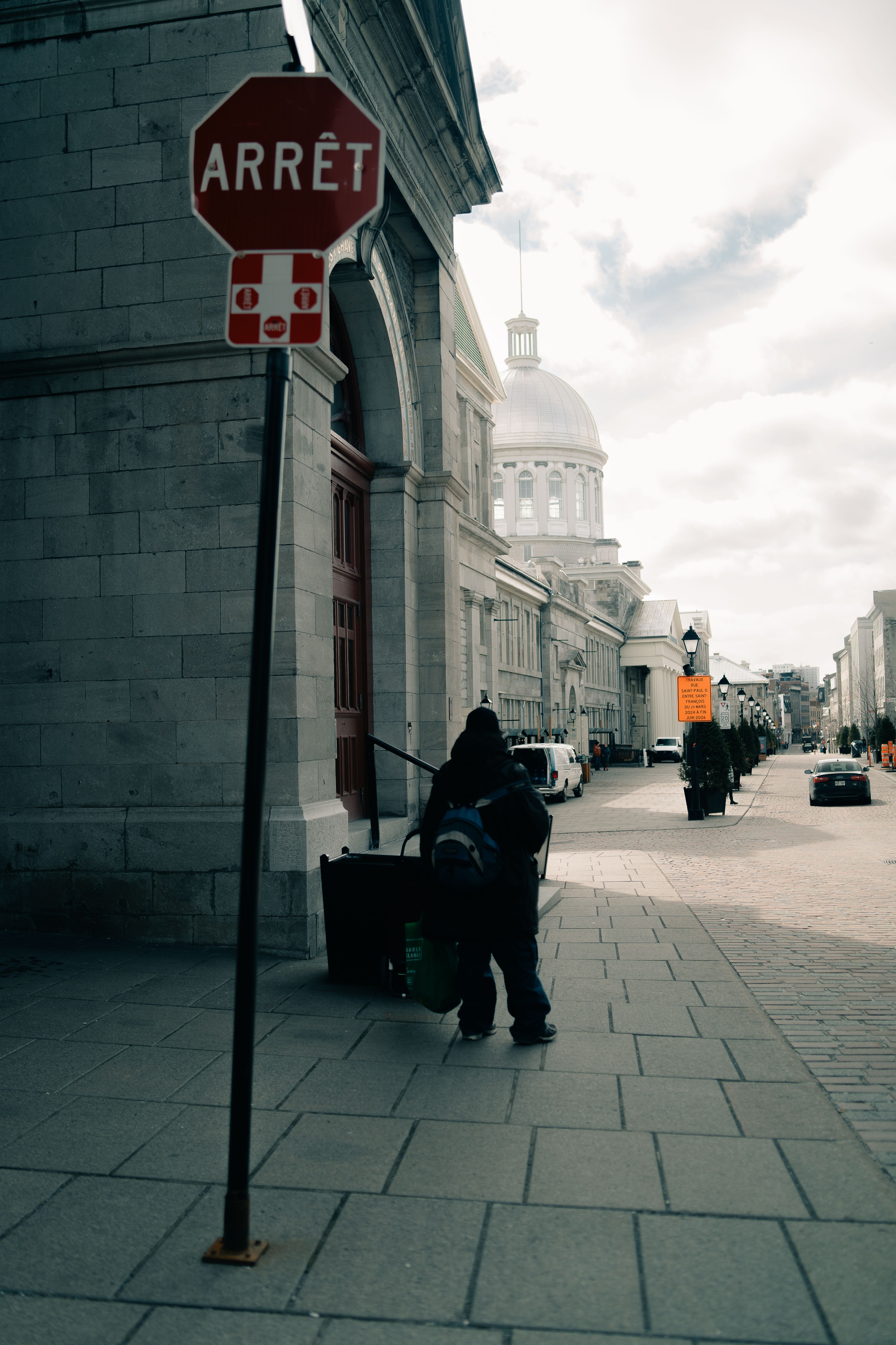 A person walking down a sidewalk next to a stop sign · Free Stock Photo