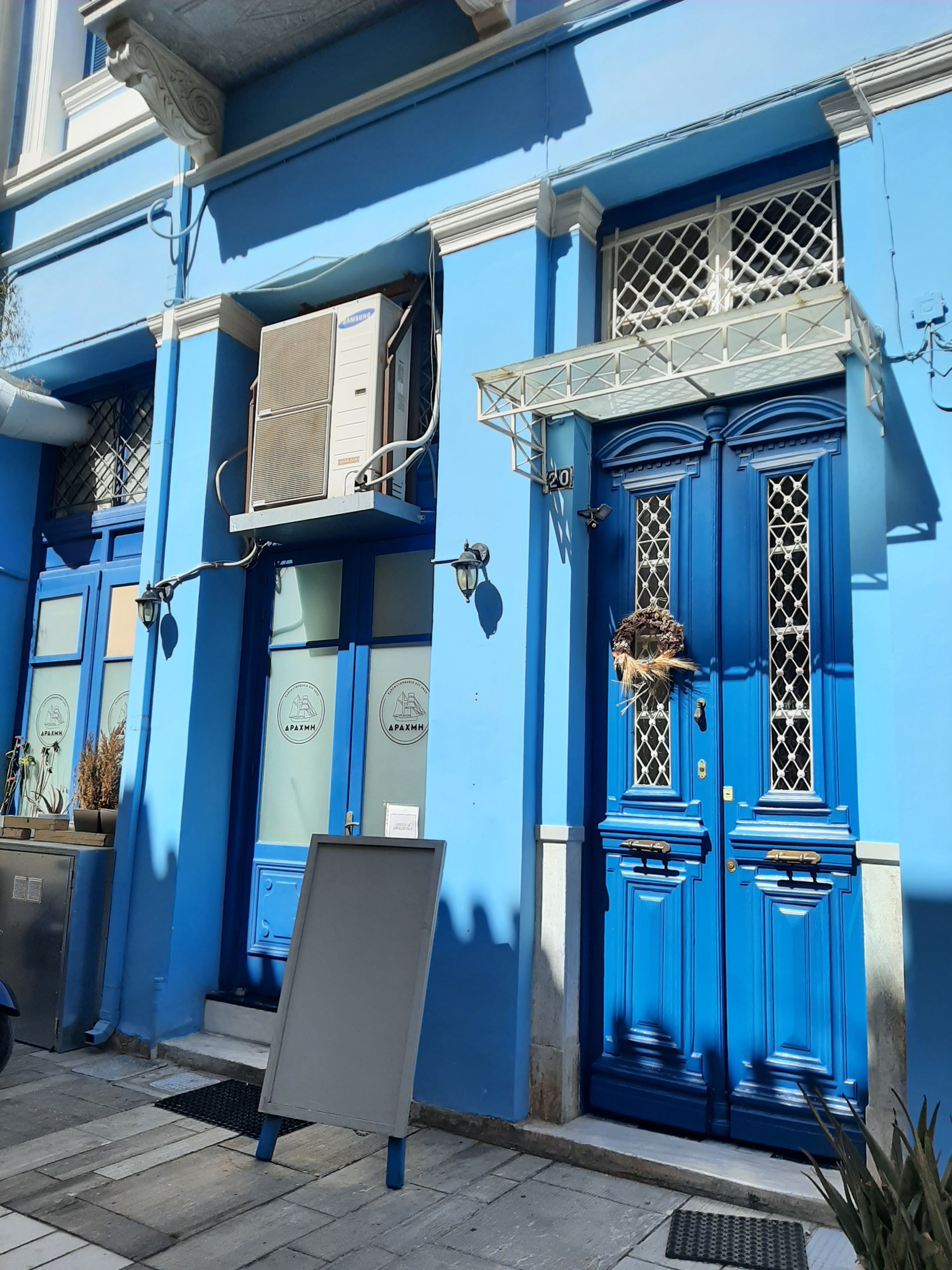 Entrance of a Blue Townhouse with Air Conditioners Above the Restaurant ...
