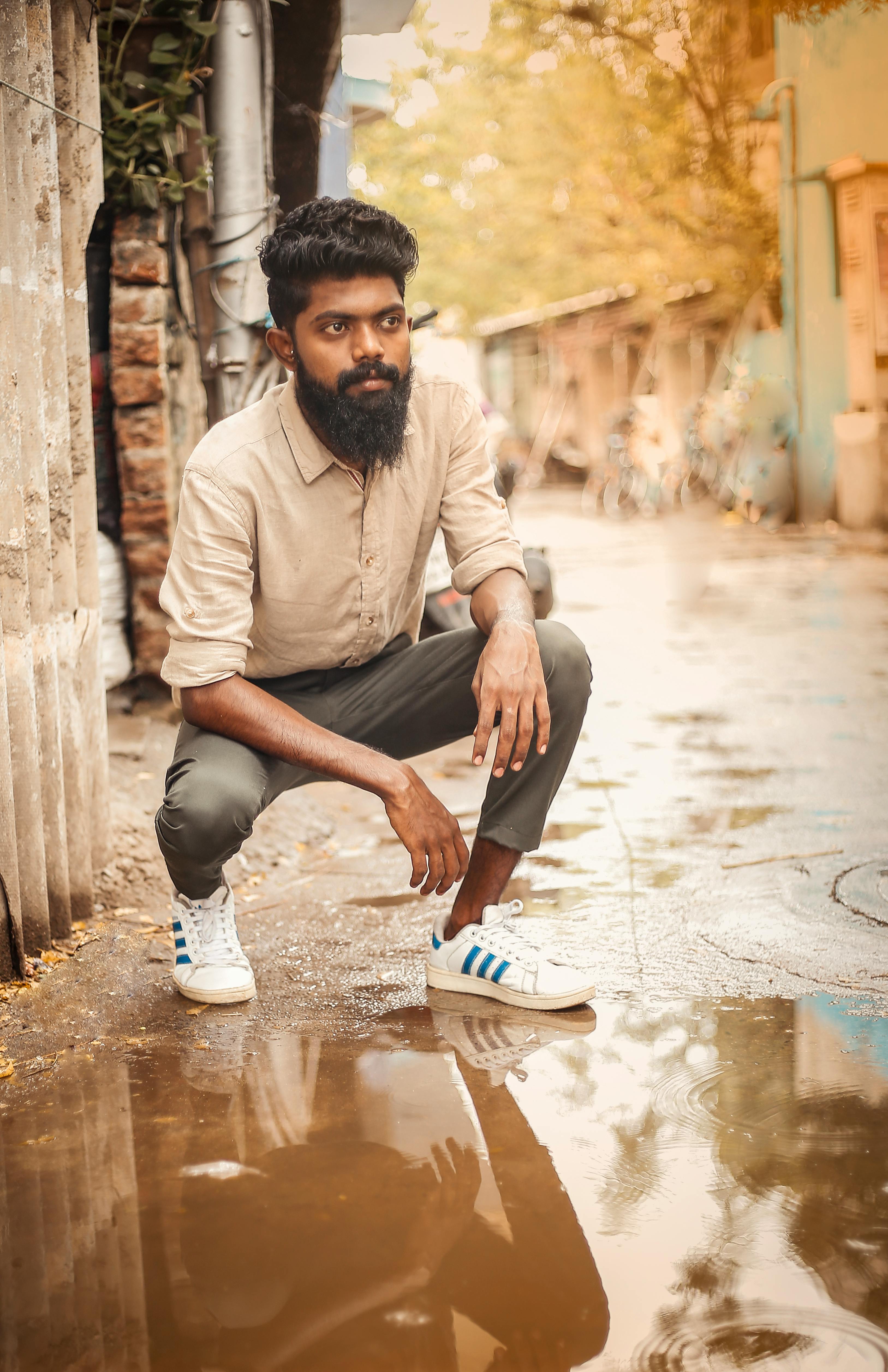 Man Wearing Beige Dress Shirt Ducking Near Puddle · Free Stock Photo