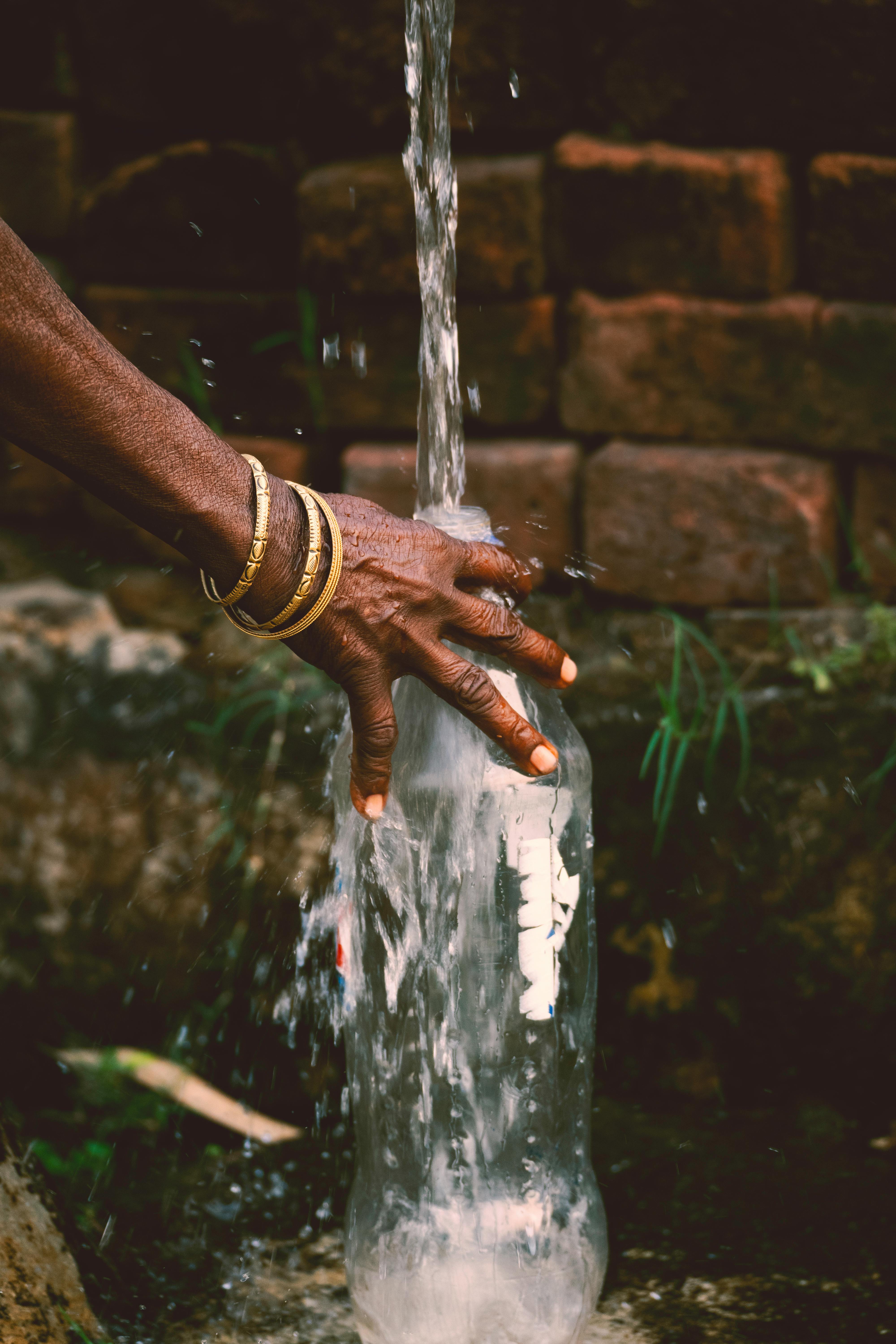 Collecting Water Into a Plastic Bottle from the Spring · Free Stock Photo