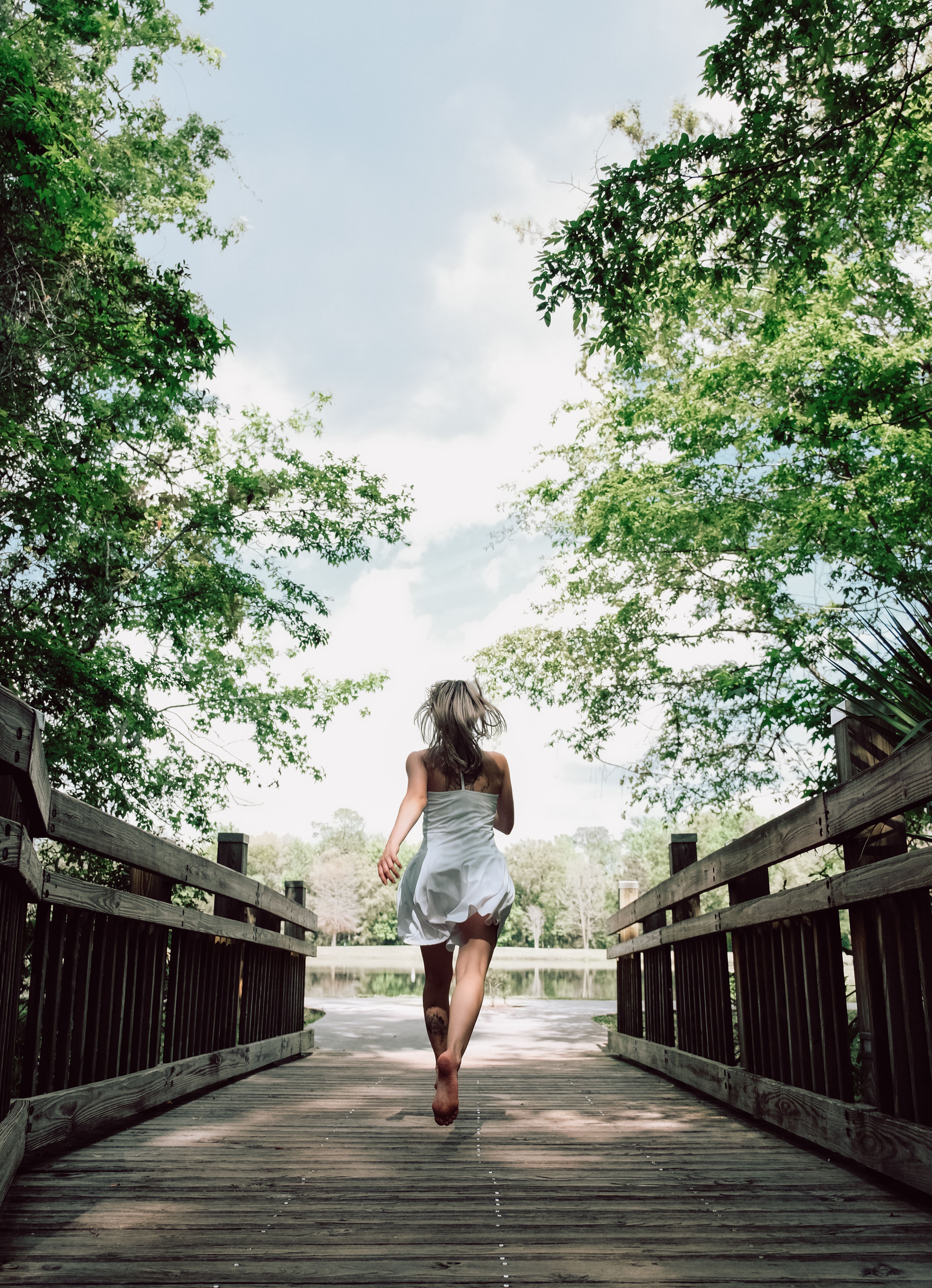 Woman in a White Sundress Running Barefoot Across a Footbridge · Free ...