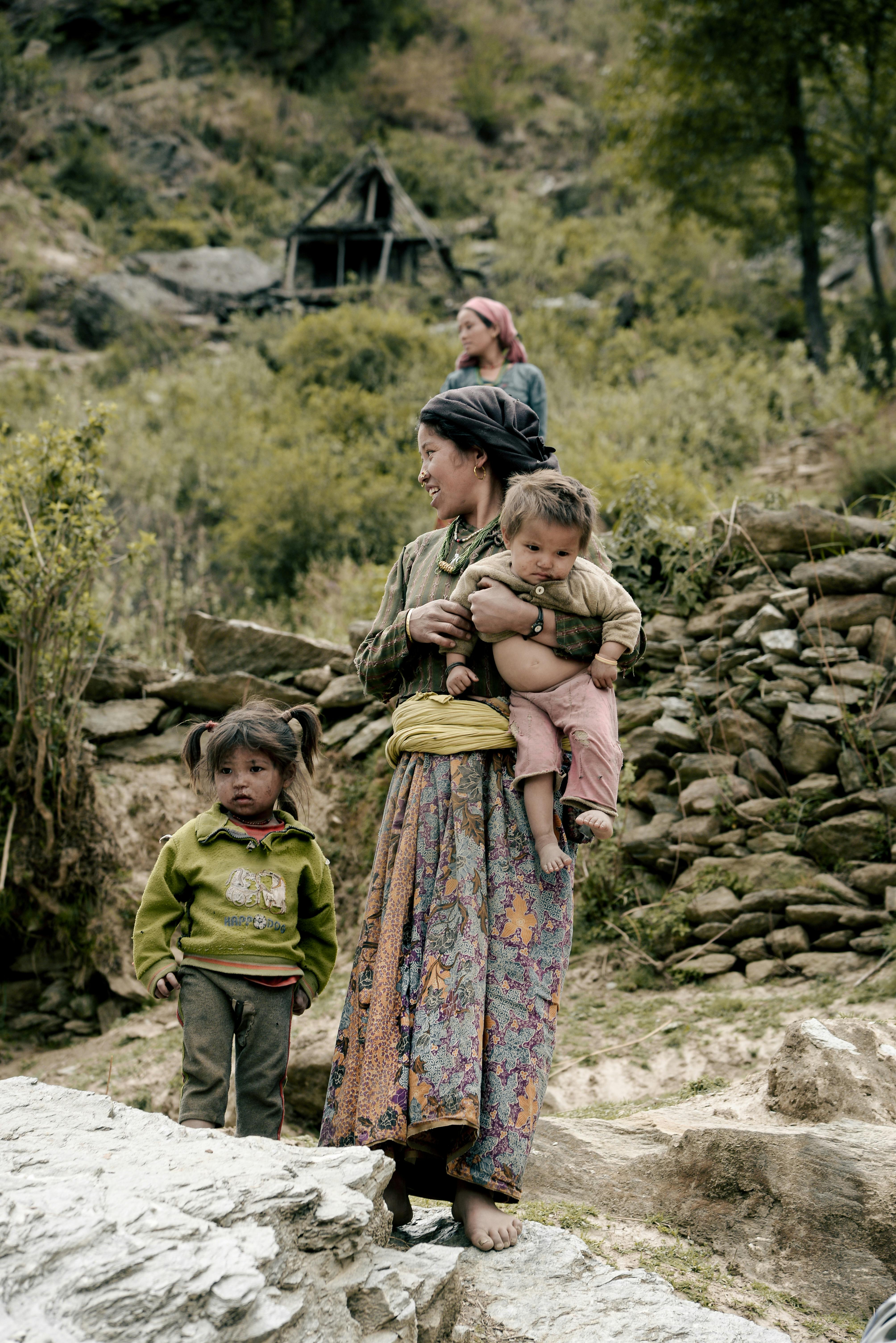 A woman carrying two children on her back · Free Stock Photo