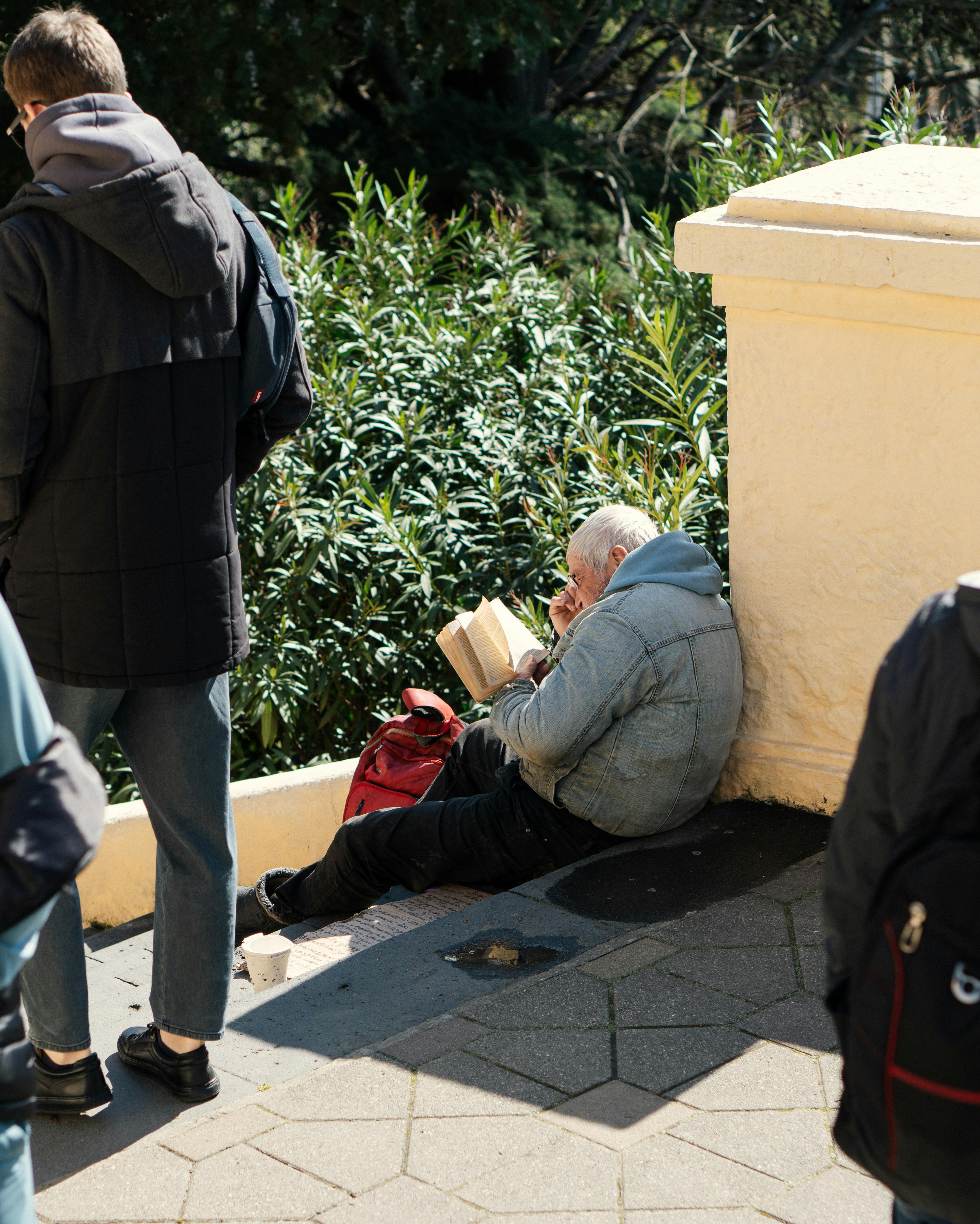 Elderly Man Reading a Book on a Pavement · Free Stock Photo