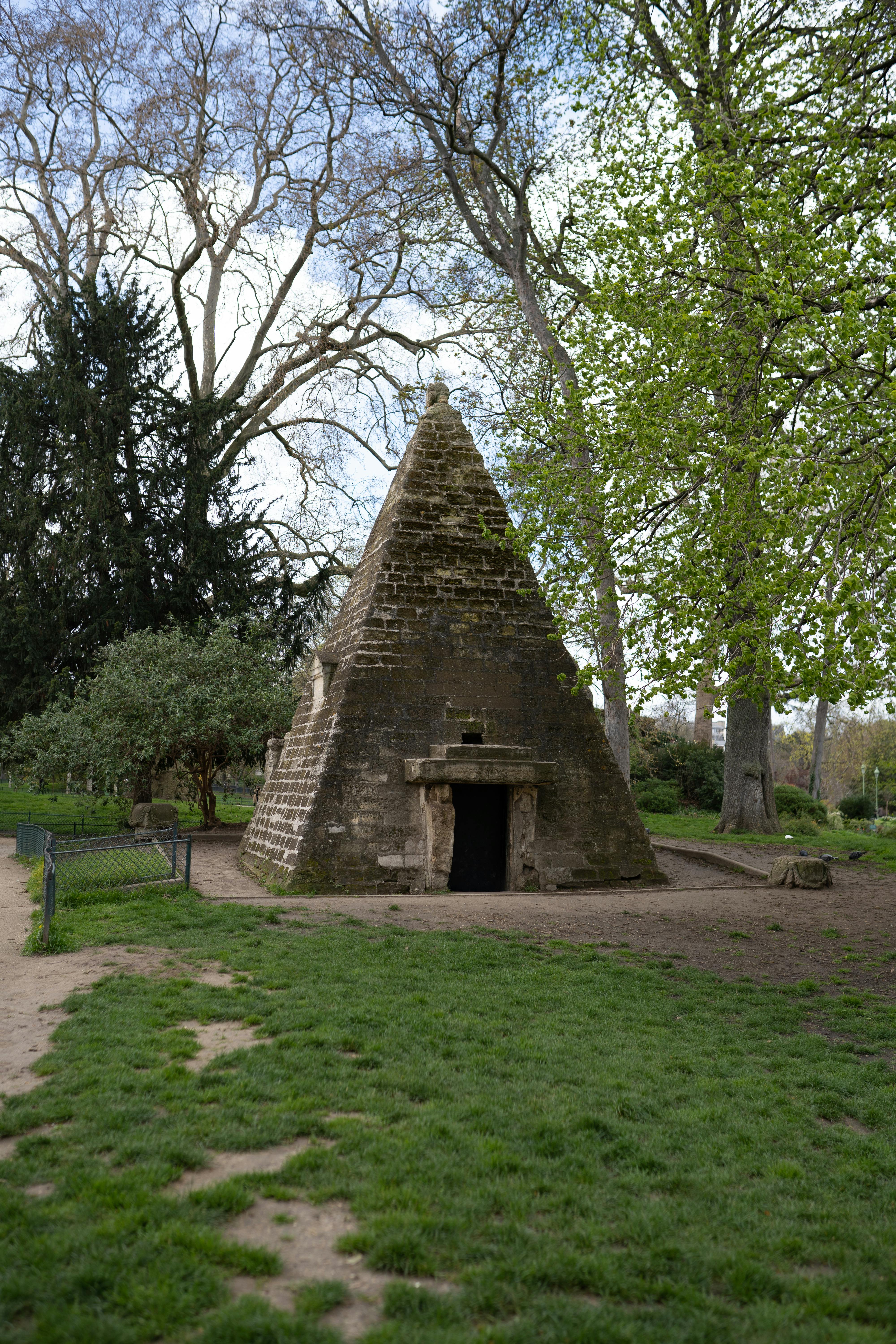 A small stone structure in a park with trees · Free Stock Photo