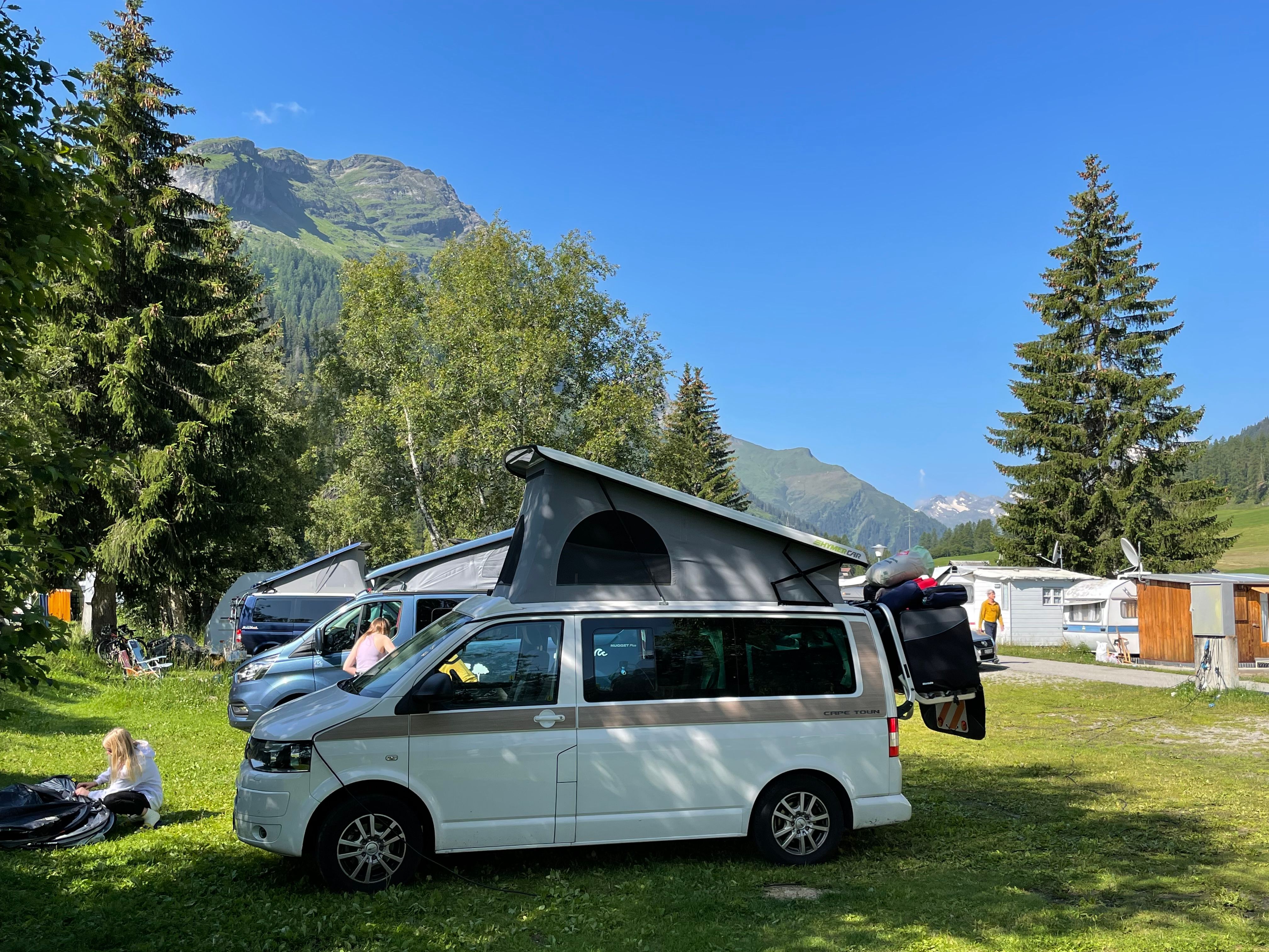 A camper van parked in the grass next to a mountain · Free Stock Photo