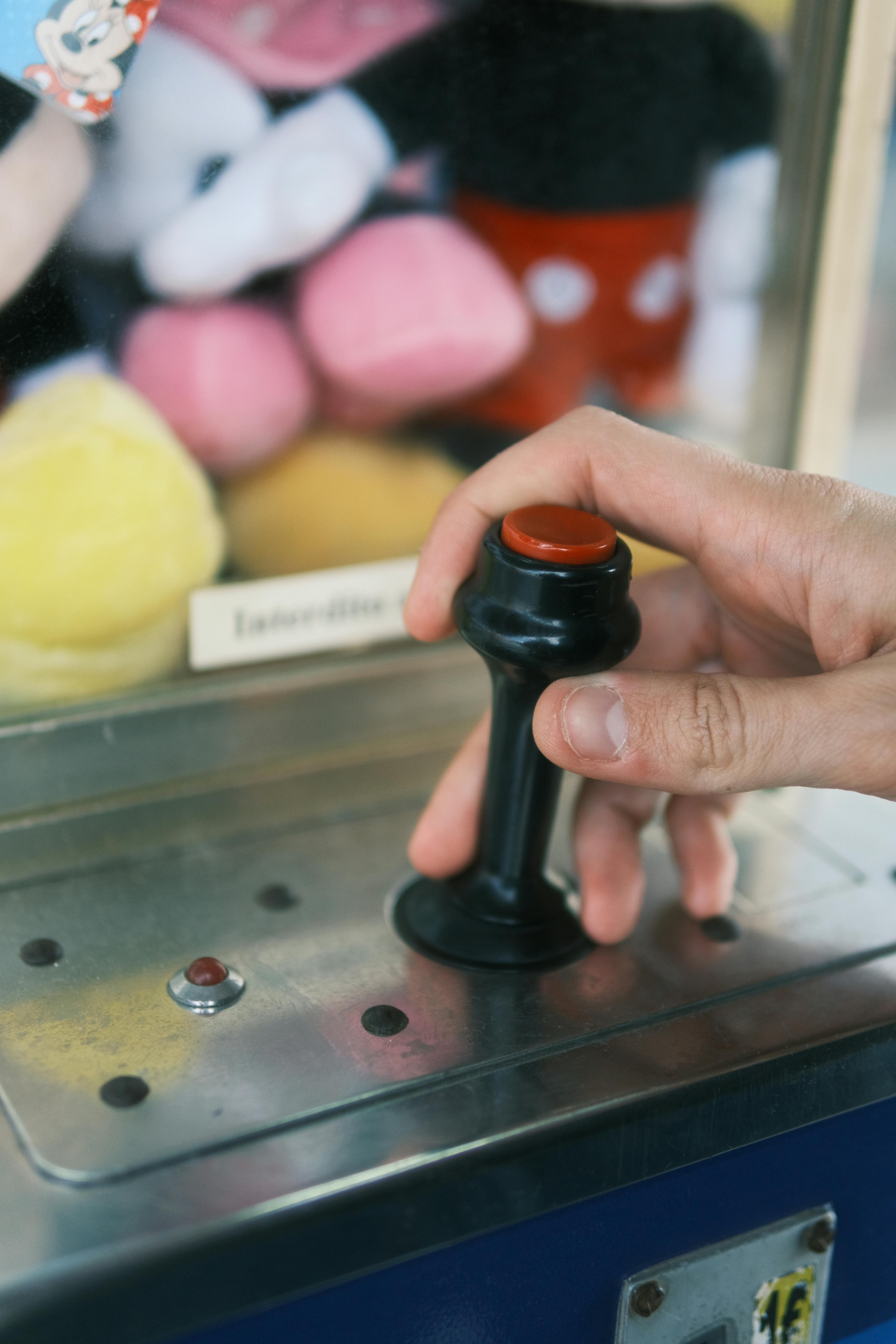 Close-up of a Person Using the Controller of a Claw Machine with Toys ...