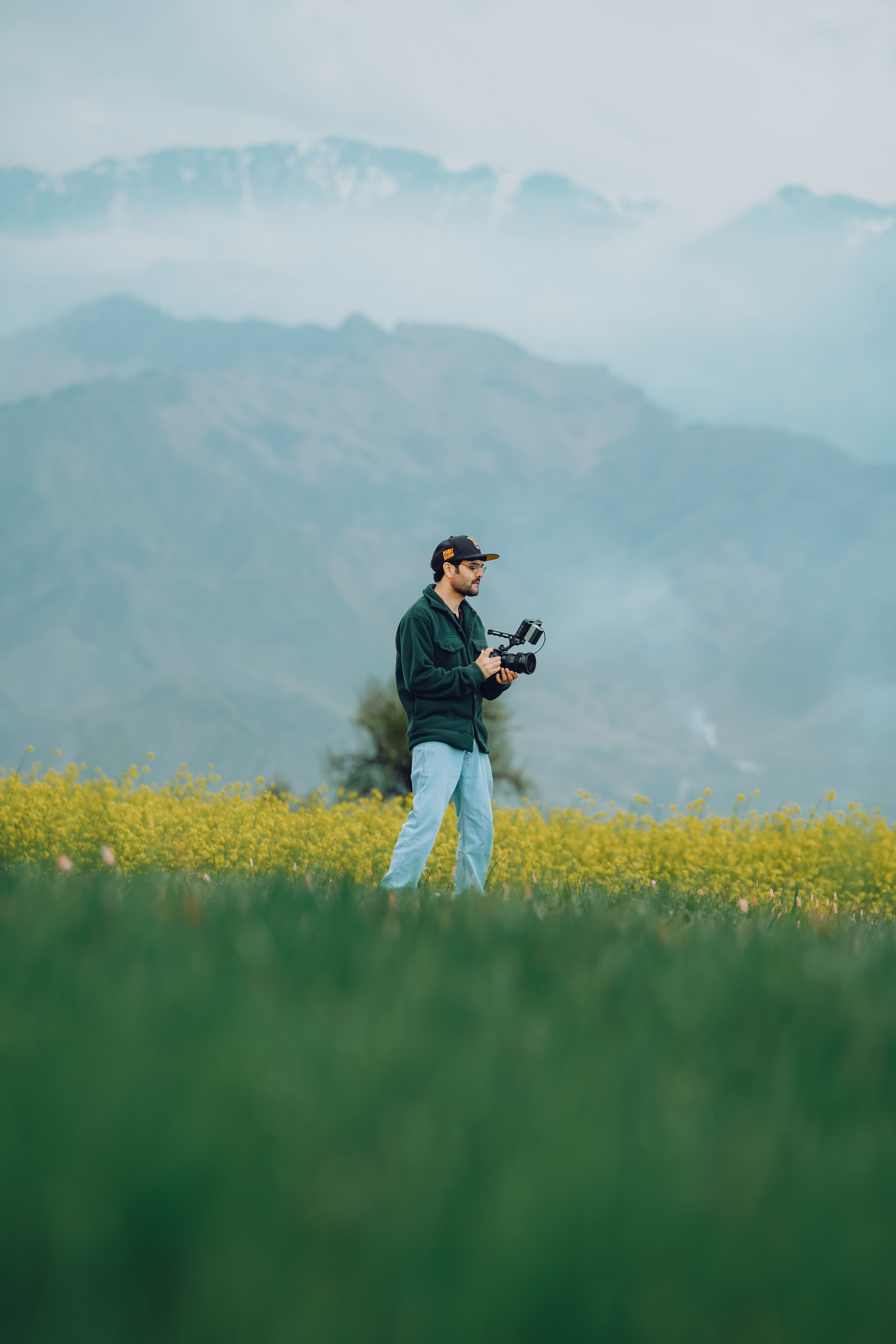 Man Standing with Camera on Meadow with Flowers · Free Stock Photo