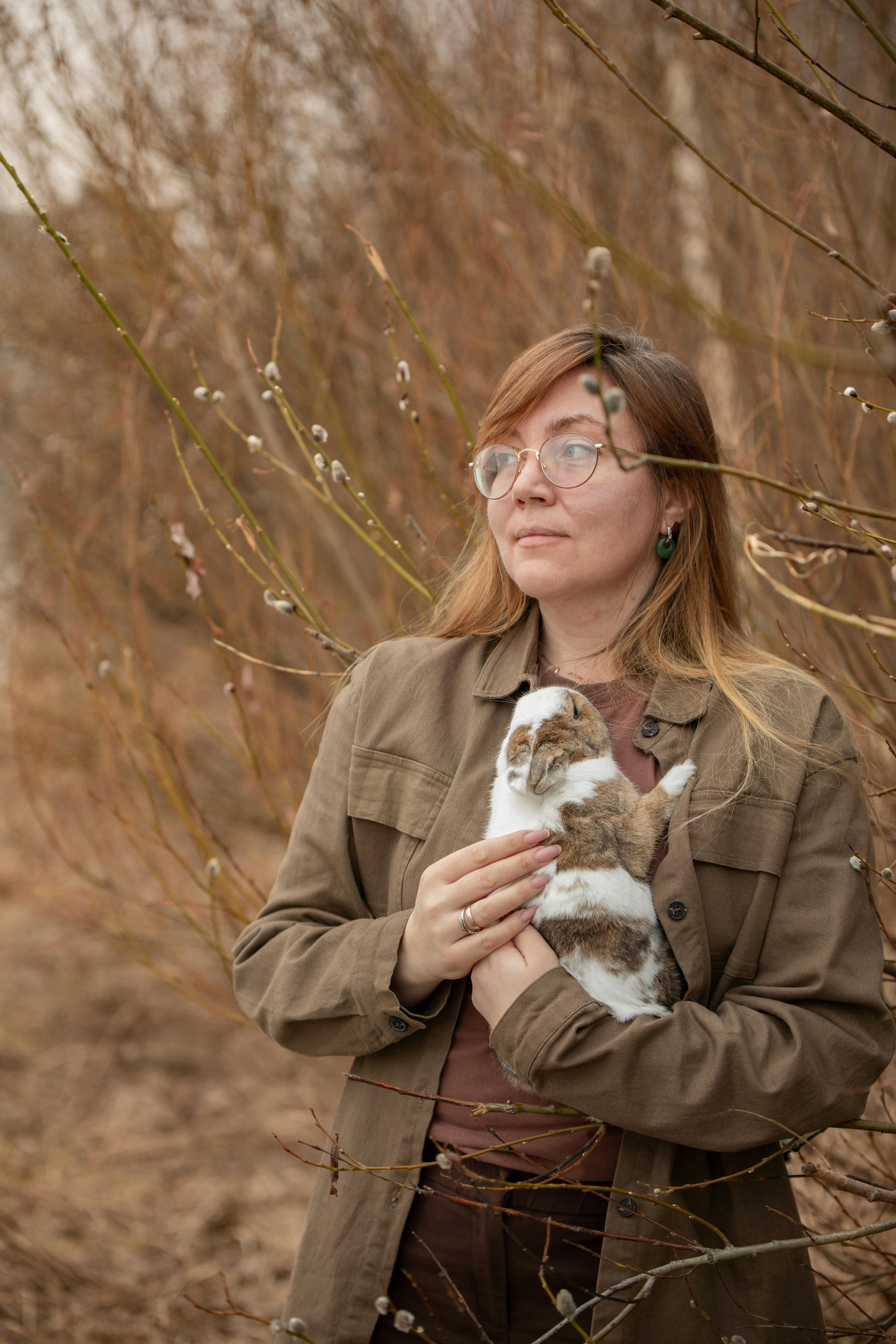 Woman Holding a Rabbit in Her Arms Standing Among the Branches of Pussy ...