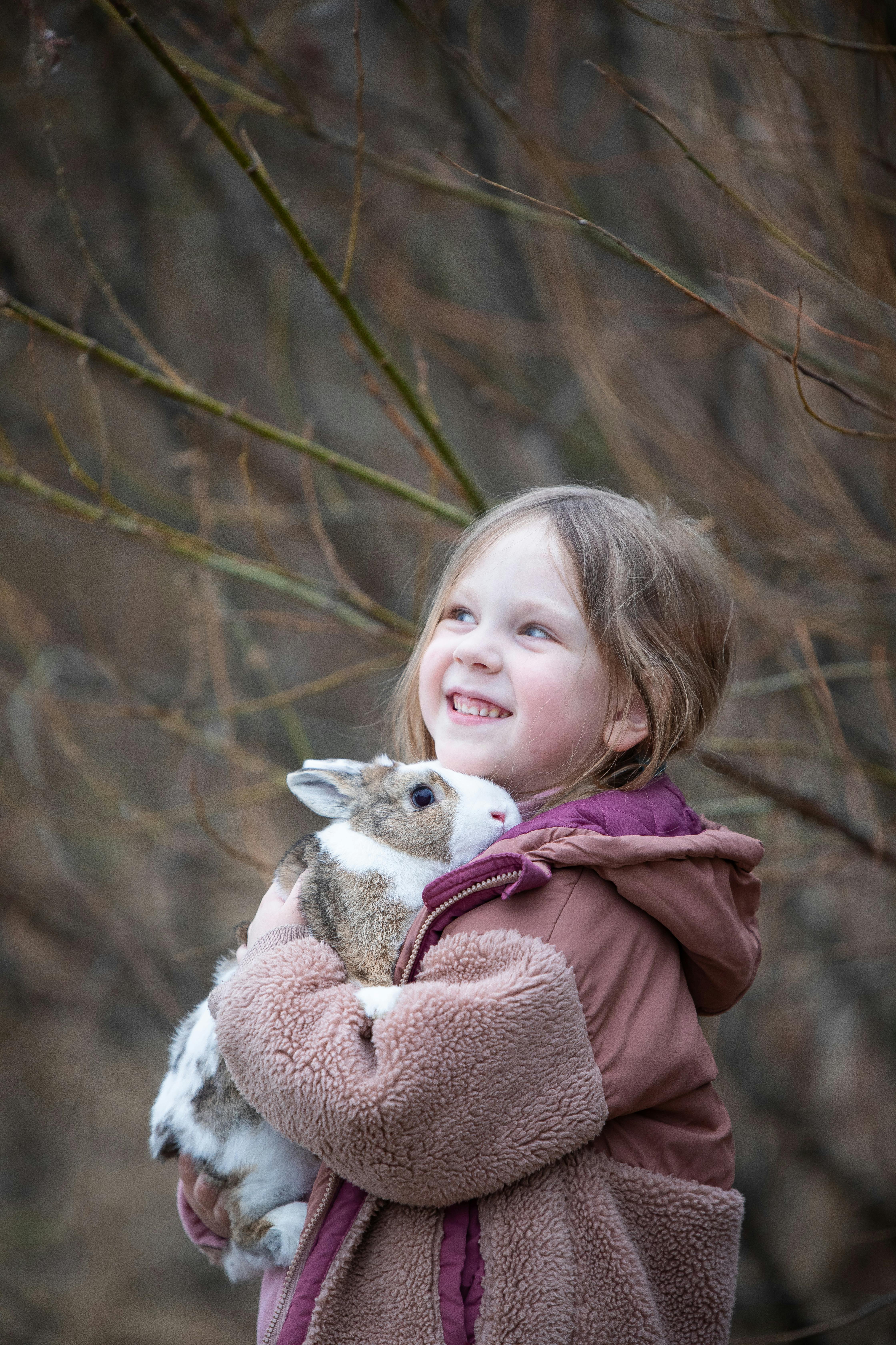 Smiling Girl in Jacket Holding Pet Rabbit · Free Stock Photo