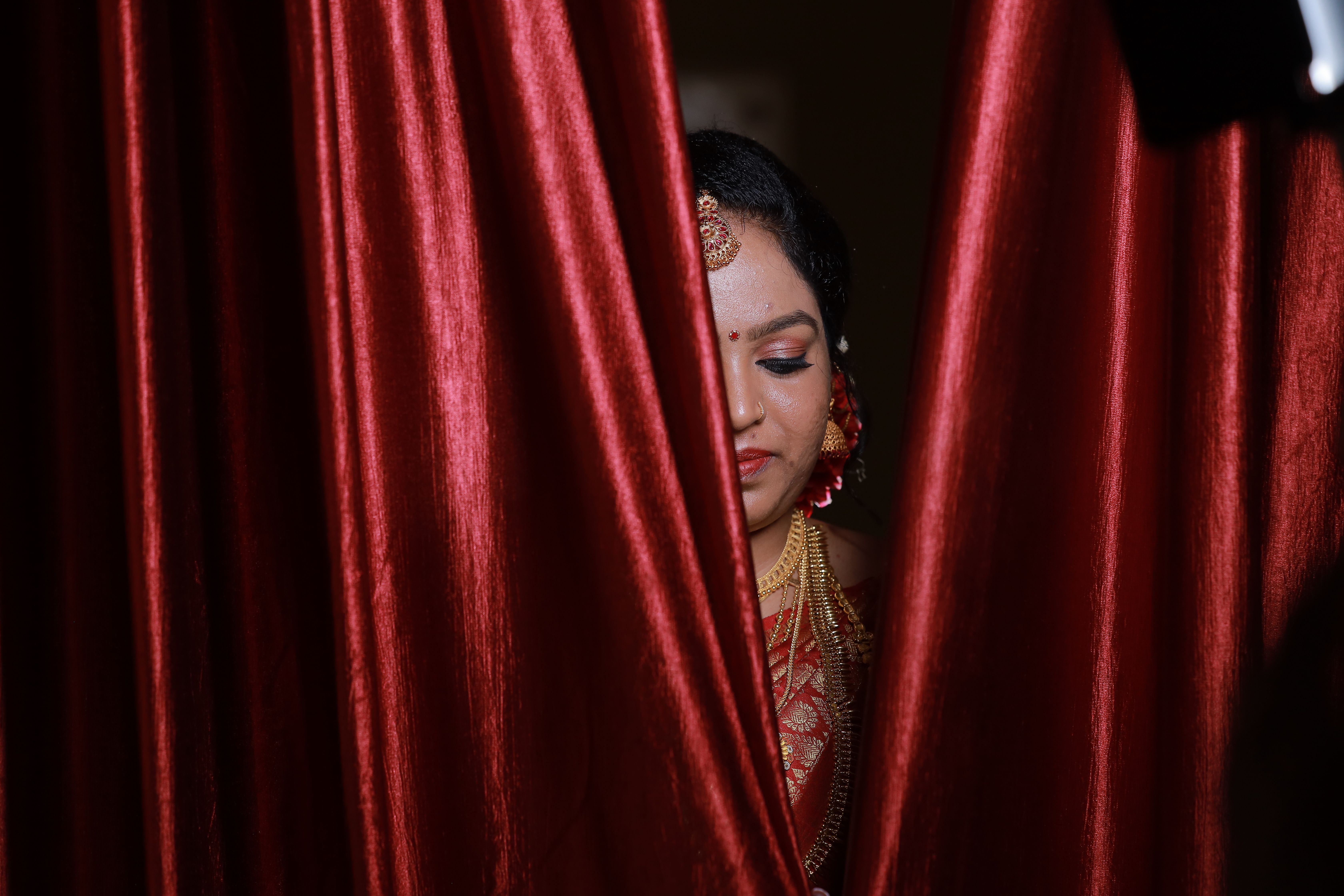A woman in a red veil looking through a curtain · Free Stock Photo