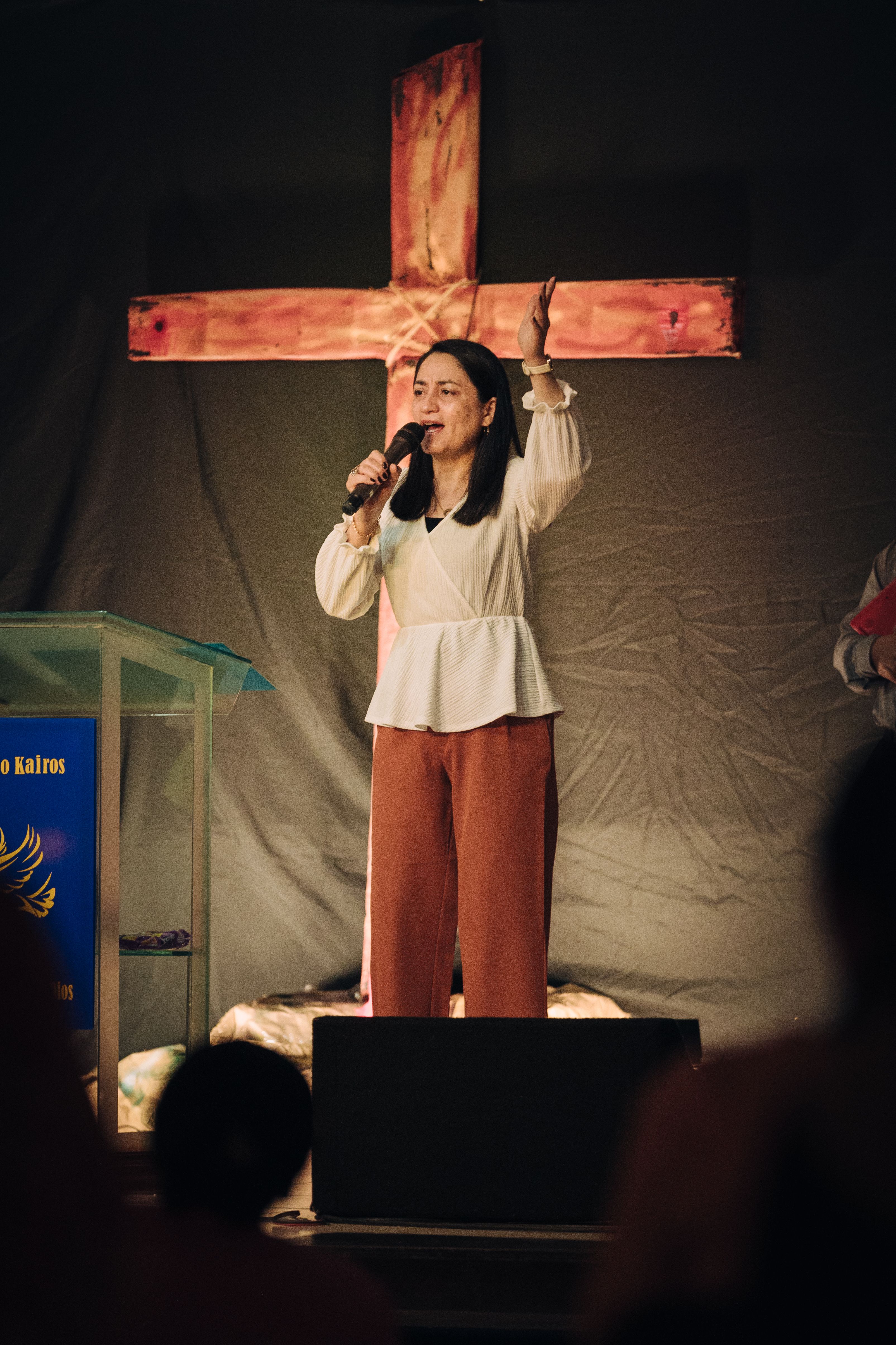 A woman is standing on stage with a cross in front of her · Free Stock ...