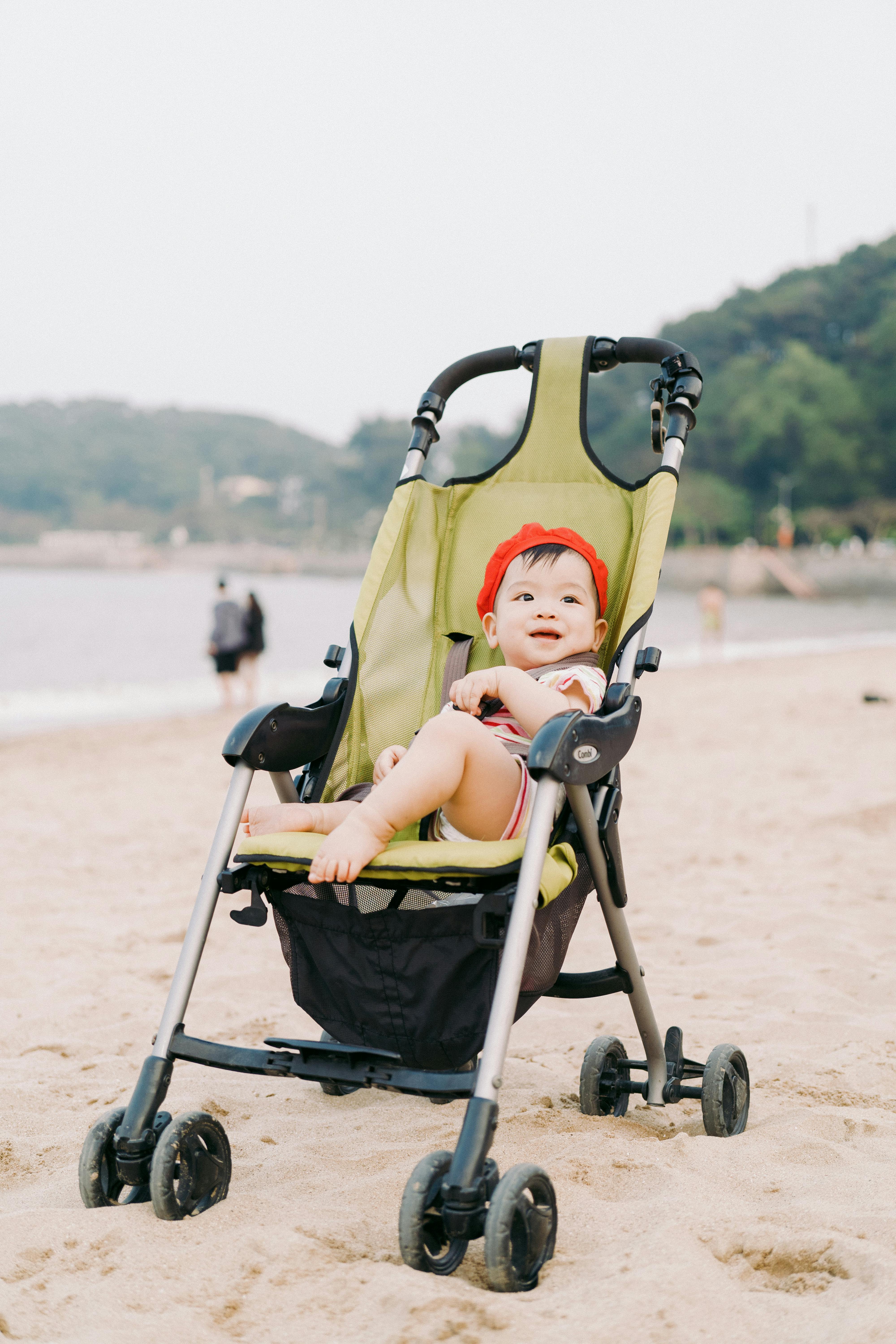 A baby in a stroller on the beach · Free Stock Photo
