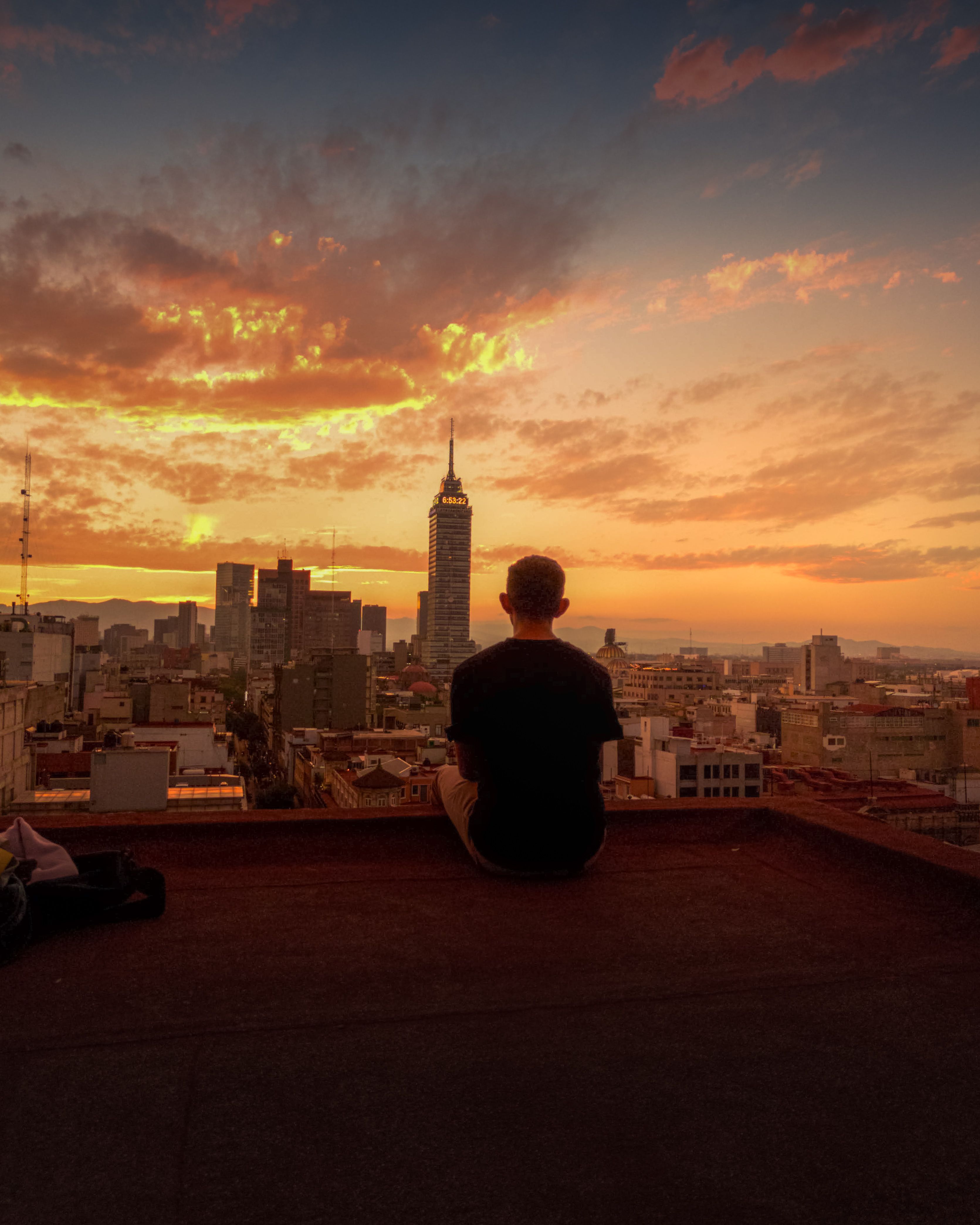 Man Sitting on Wall with Torre Latinoamericana in Mexico City at Sunset ...