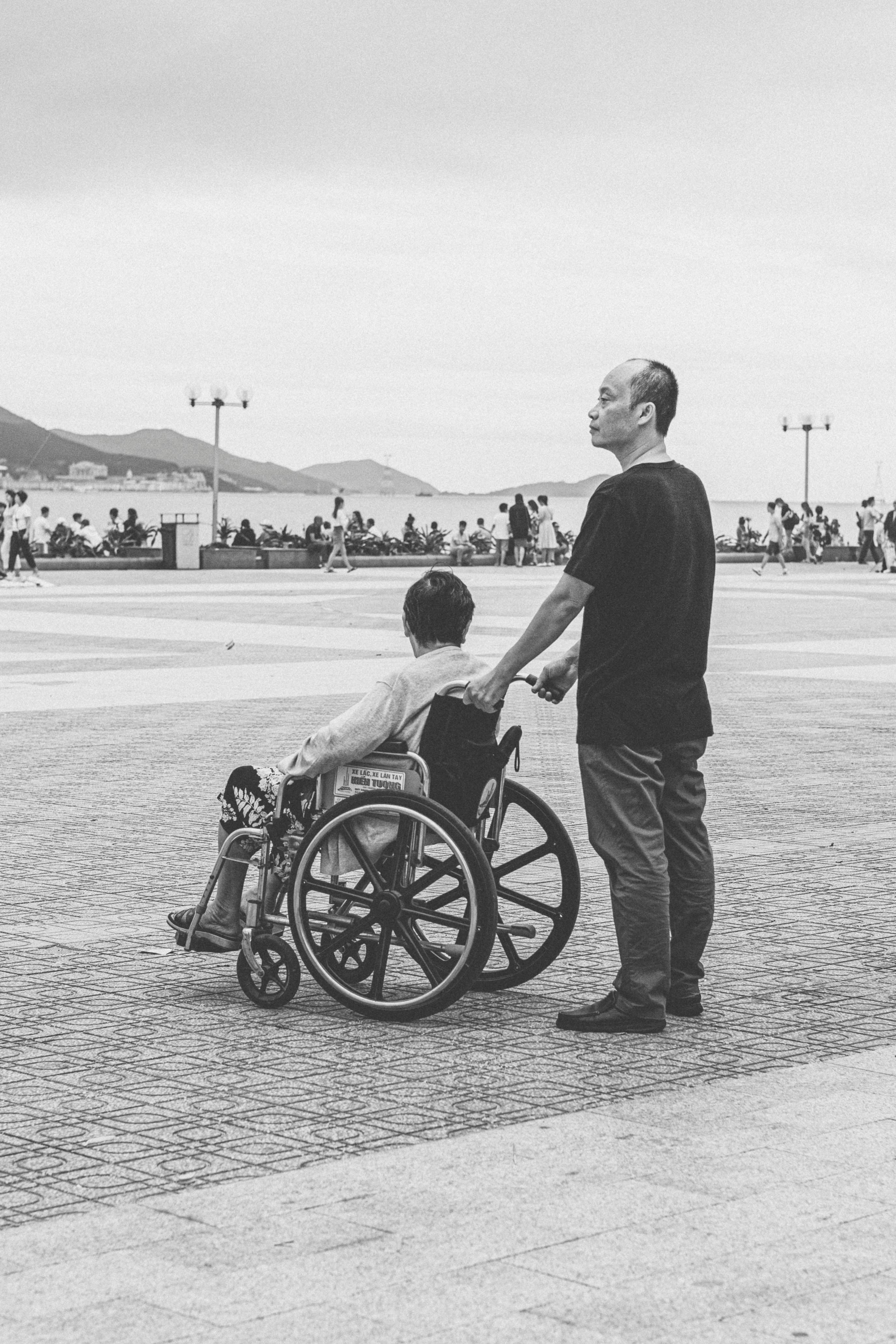 Man Pushing a Woman in a Wheelchair Along a Seaside Promenade · Free ...
