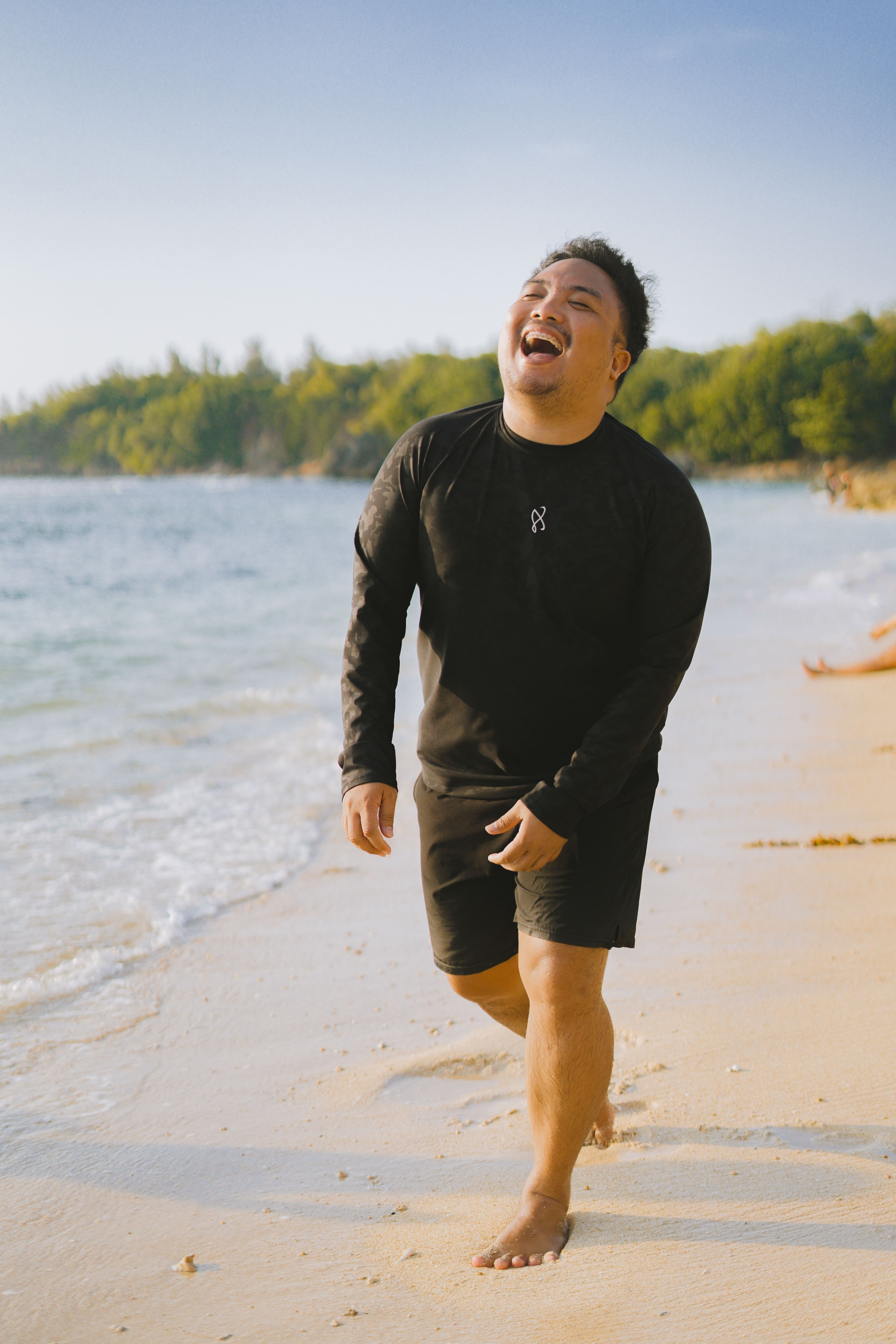 Man in Sweatshirt Laughing on Beach · Free Stock Photo