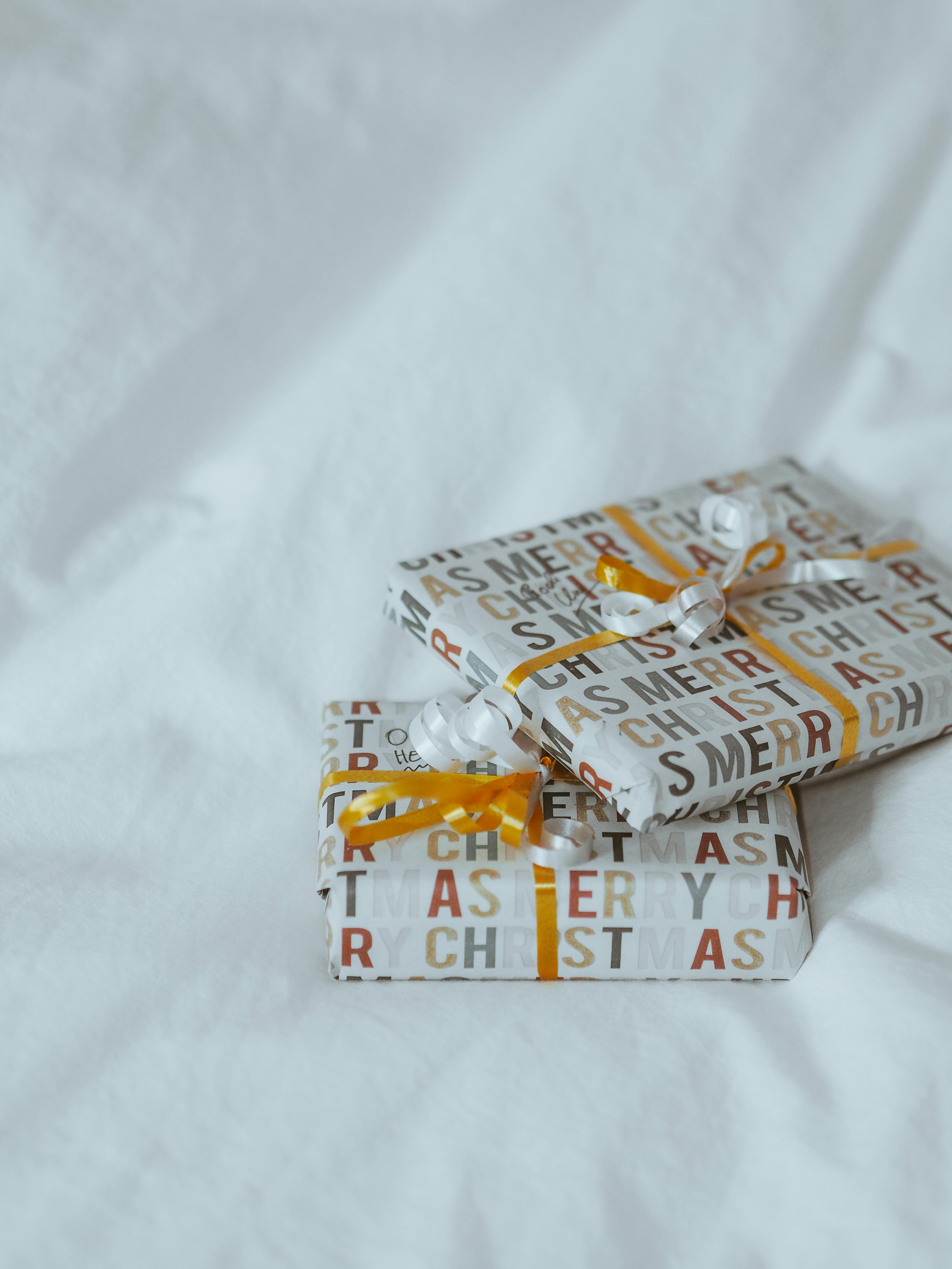 Two wrapped presents on a white bed · Free Stock Photo