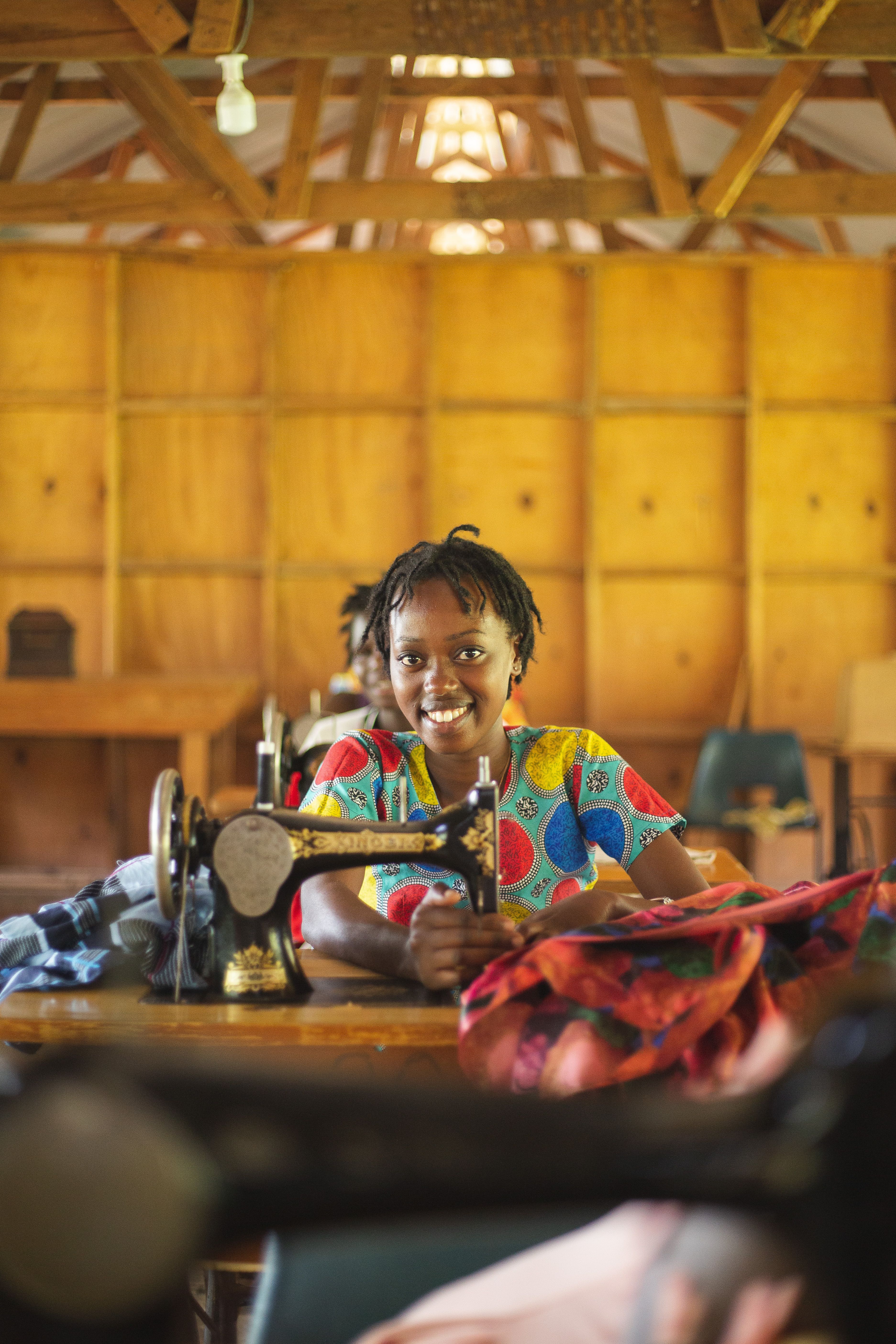 A young girl smiles while sewing at a sewing machine · Free Stock Photo