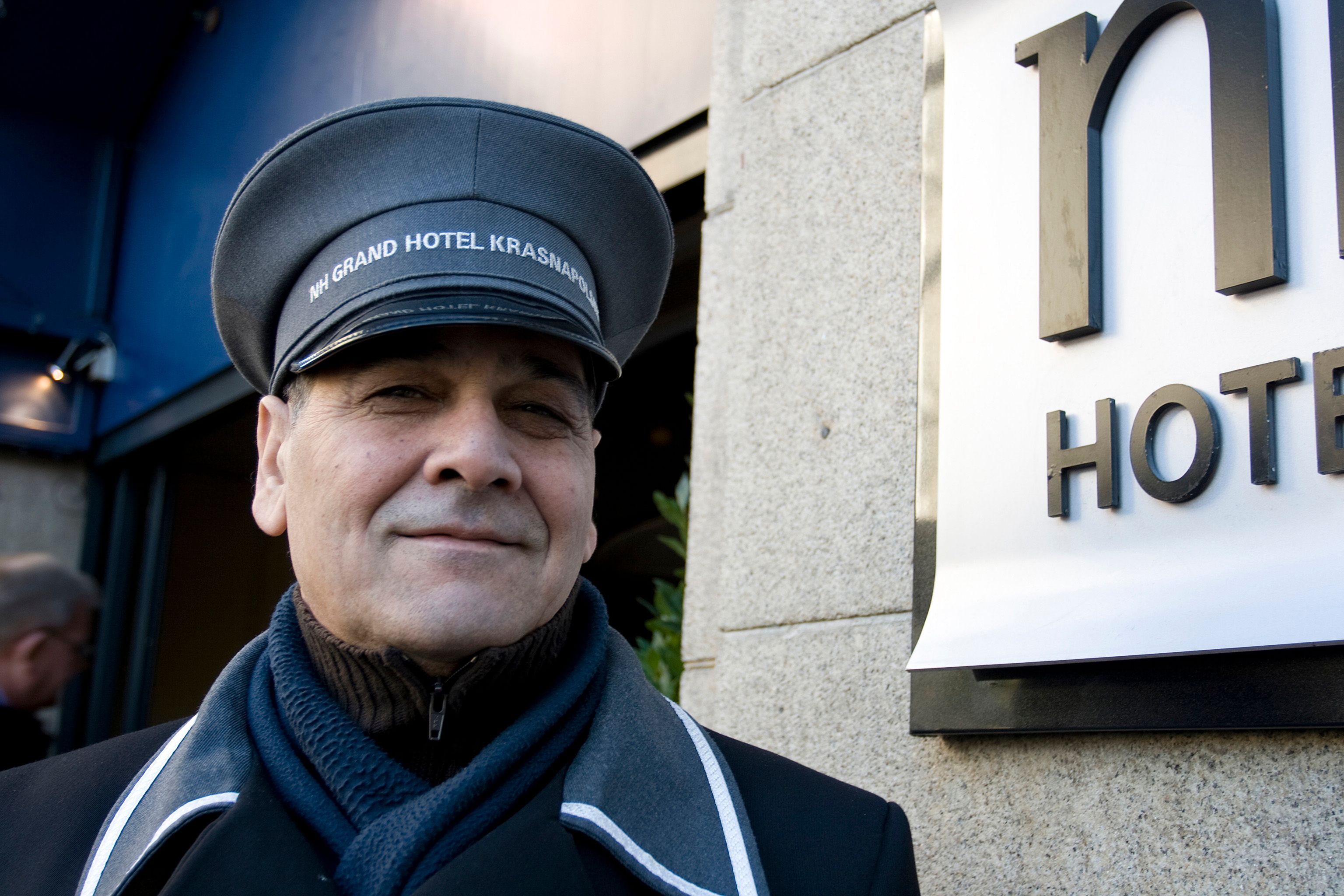 A Smiling Hotel Worker in a Uniform Standing in Front of the Building ...